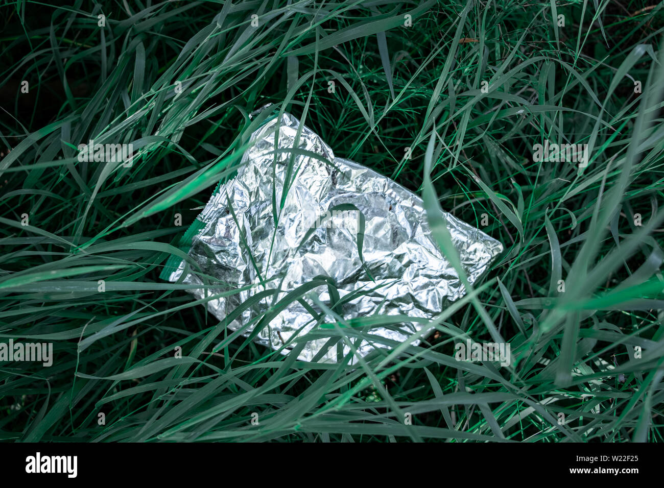 Plastic bag in green grass, nature pollution concept. Piece of plastic ...