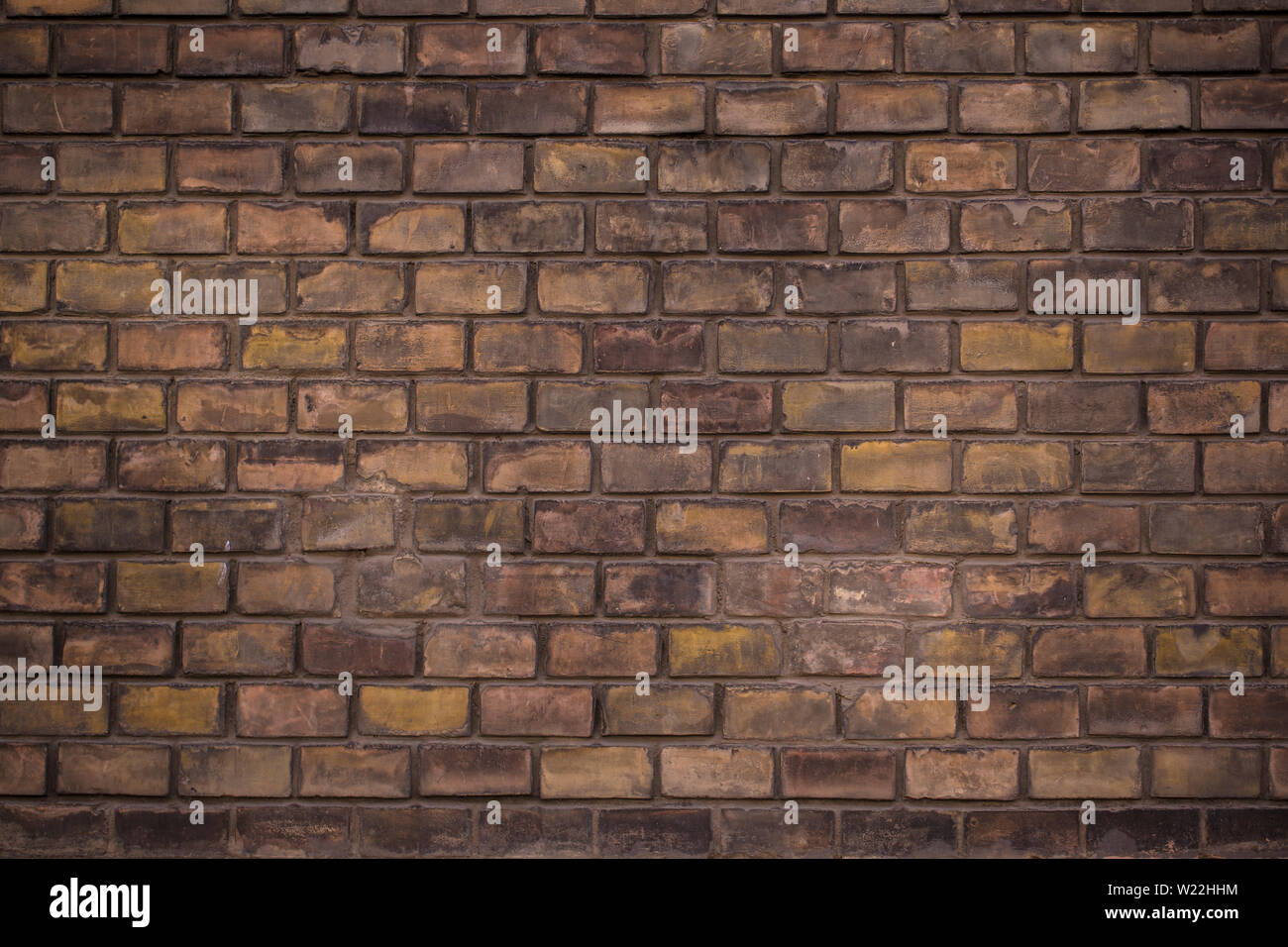 Wall made from red and sometimes colorful bricks of regular shapes and ...