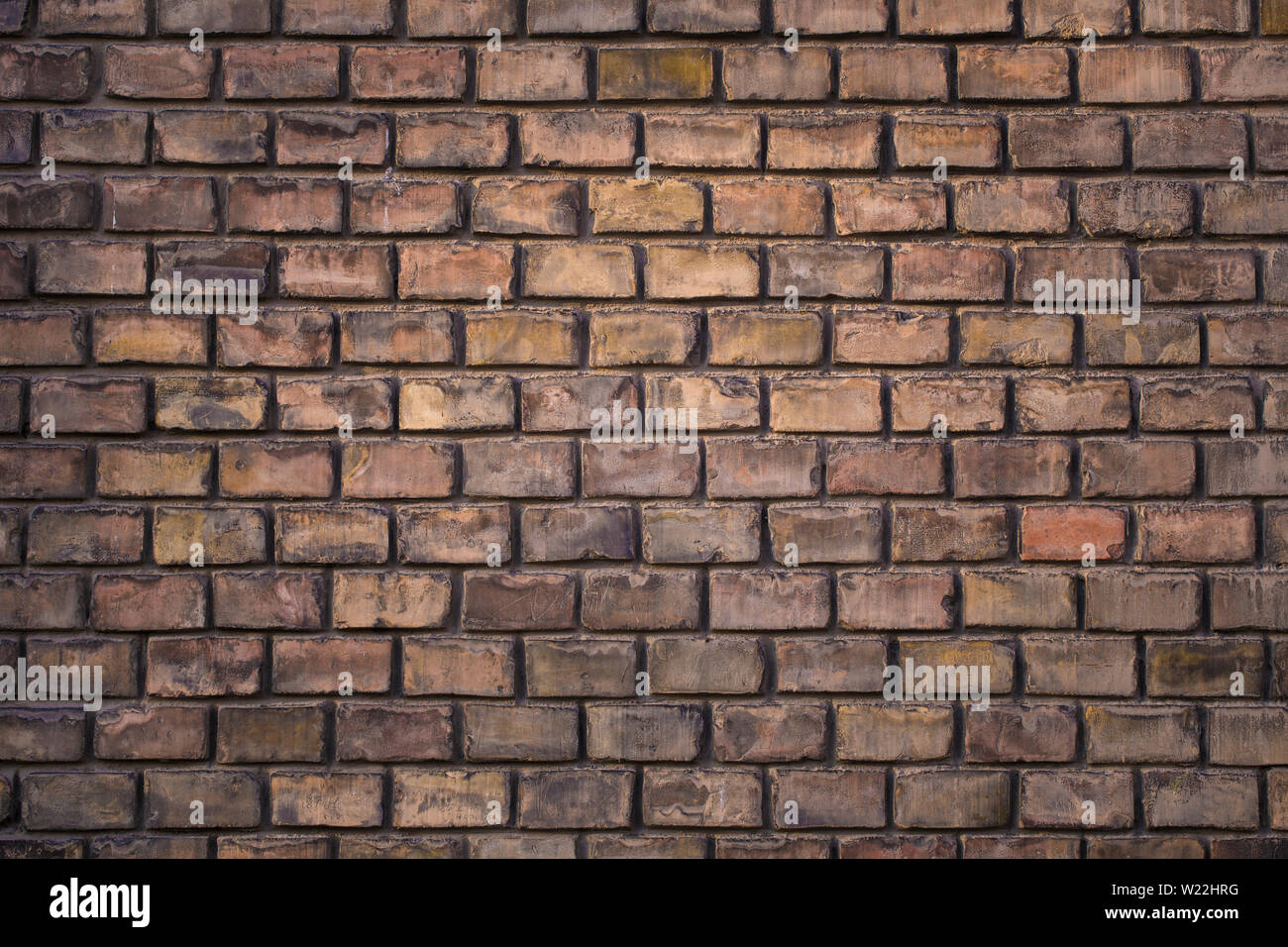 Wall made from red and sometimes colorful bricks of regular shapes and ...