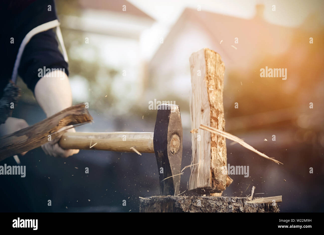 A man in the village , dressed in a black jacket, chopping with an ax a ...
