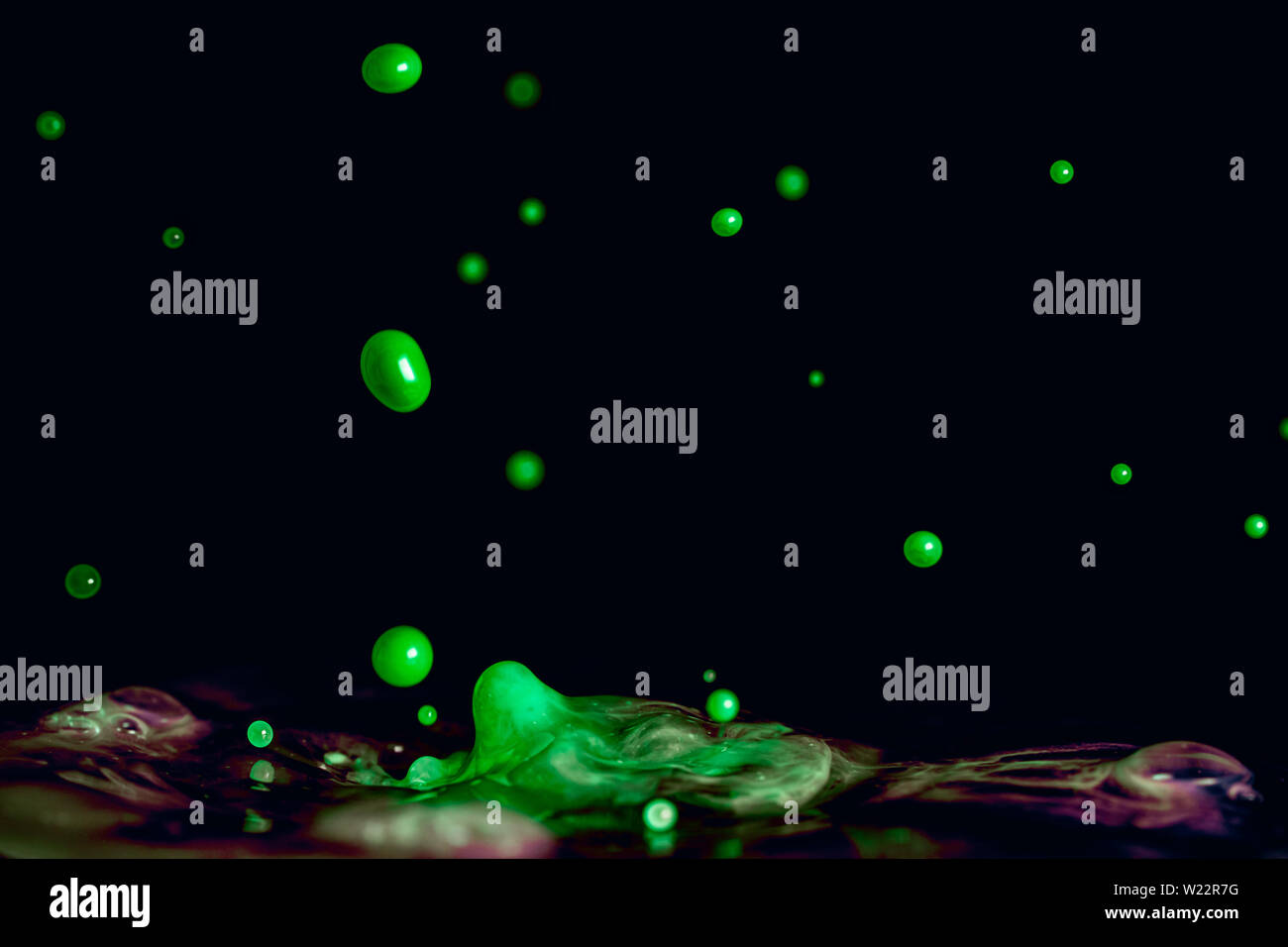 A colorful splash of vivid green liquid isolated against a black ...