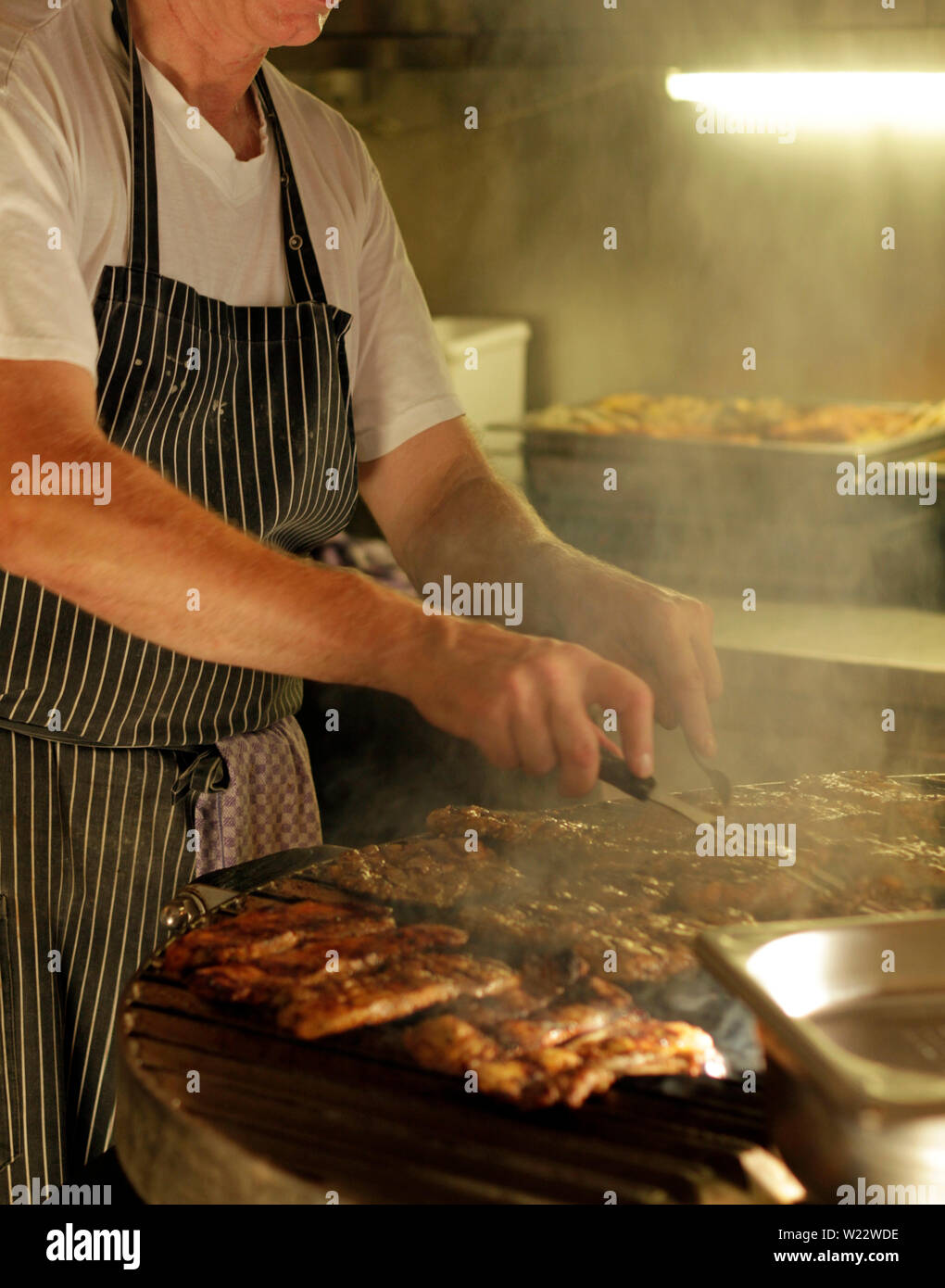 Man wearing an apron working the bbq grill Stock Photo - Alamy