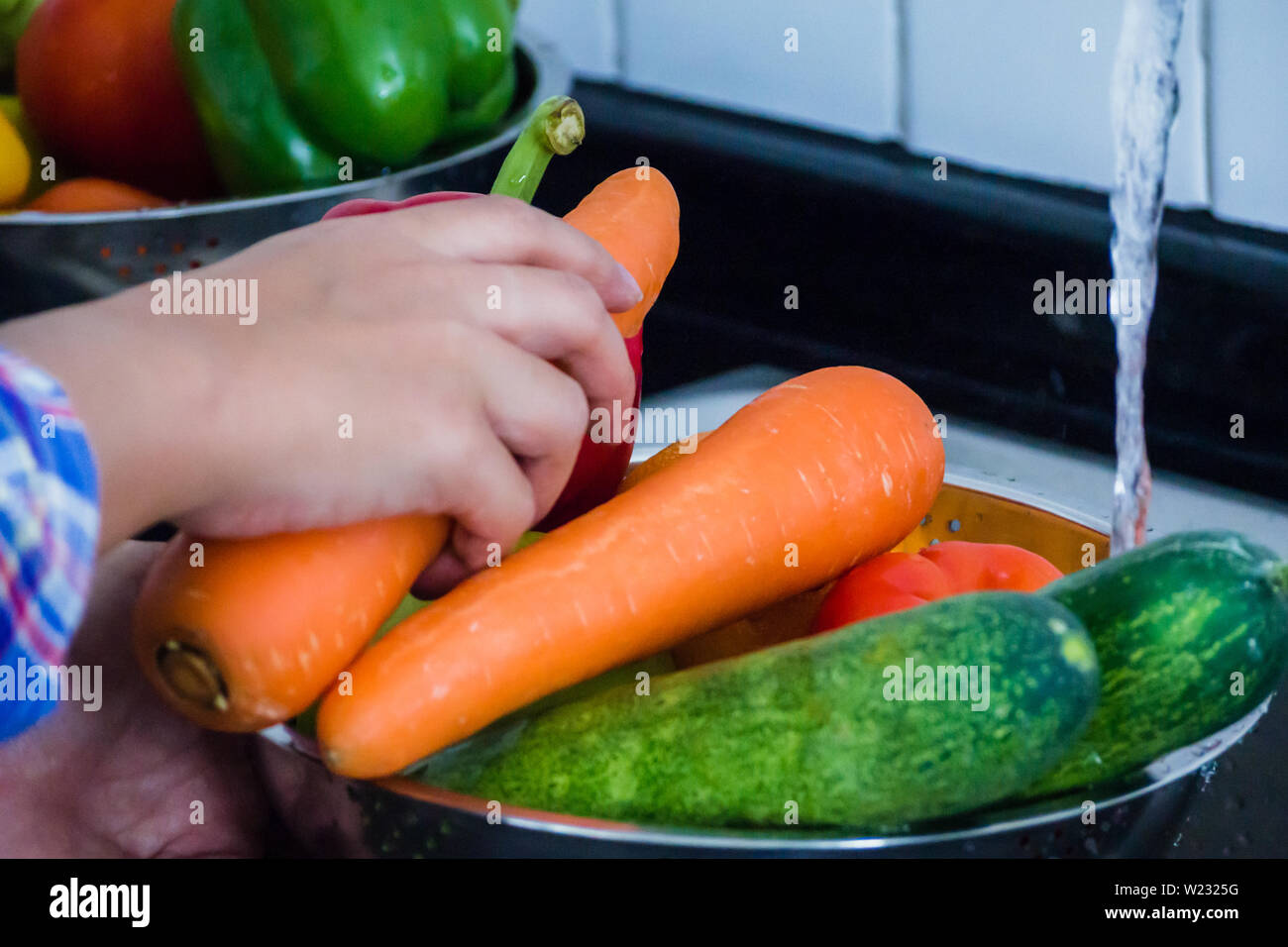 Young woman washing carrot to remove pesticides before cooking in ...