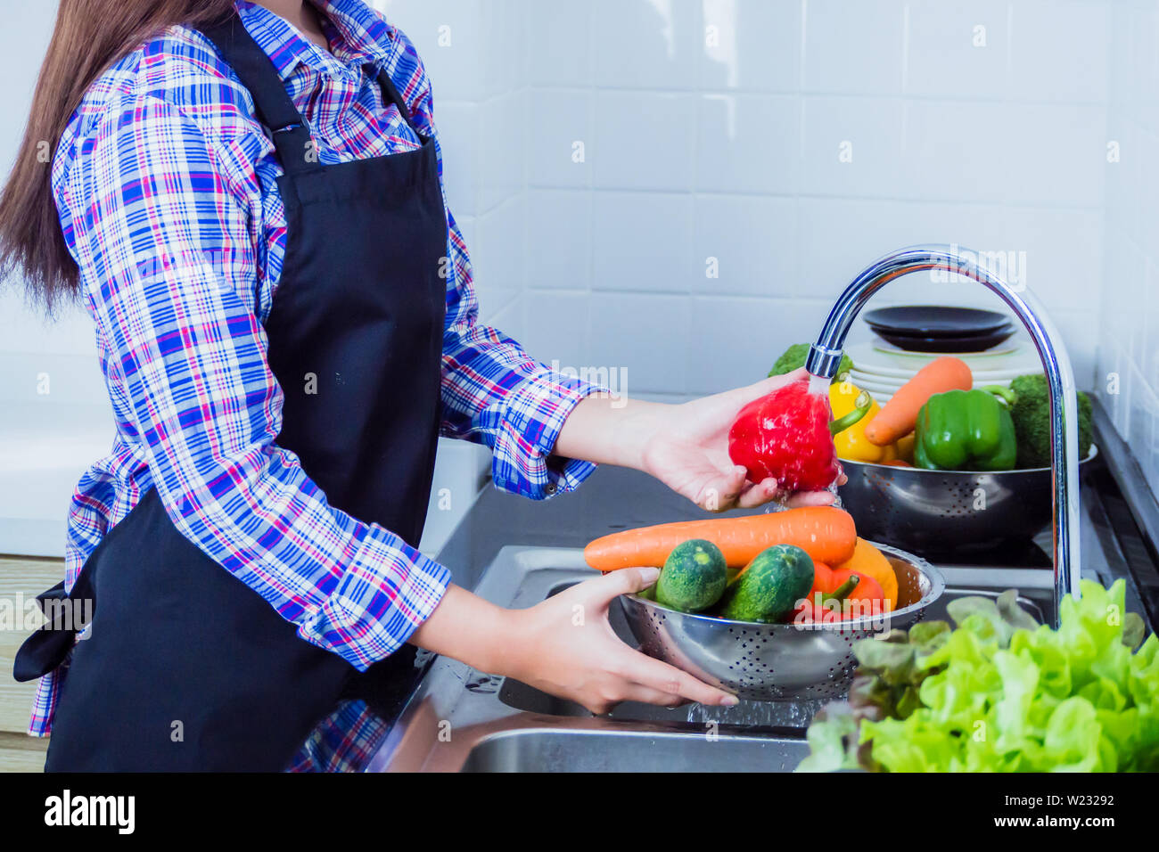 Young woman washing lettuce and apples to remove pesticides before ...