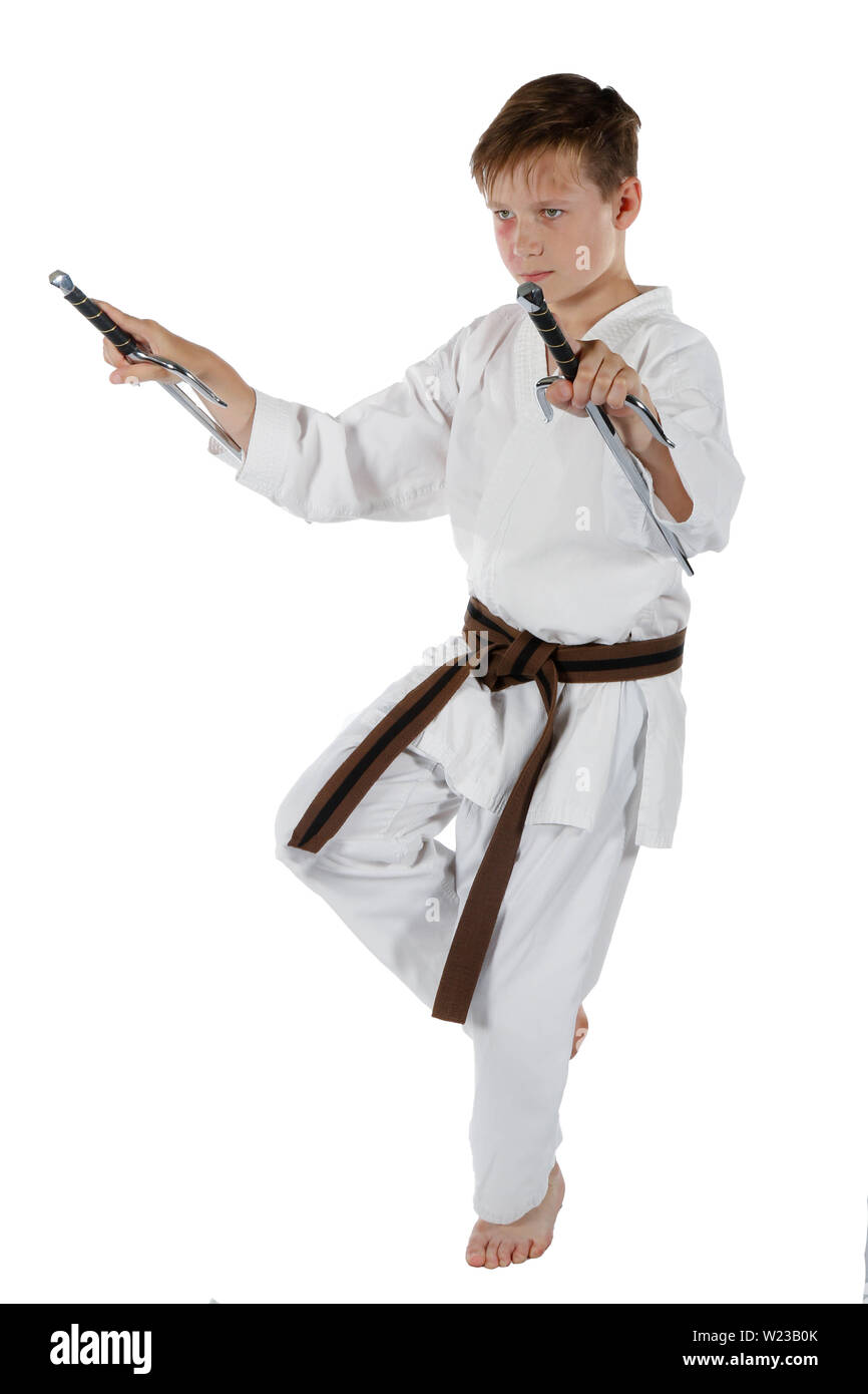 Teenage caucasian boy wearing a karate uniform performing kata with Sai ...