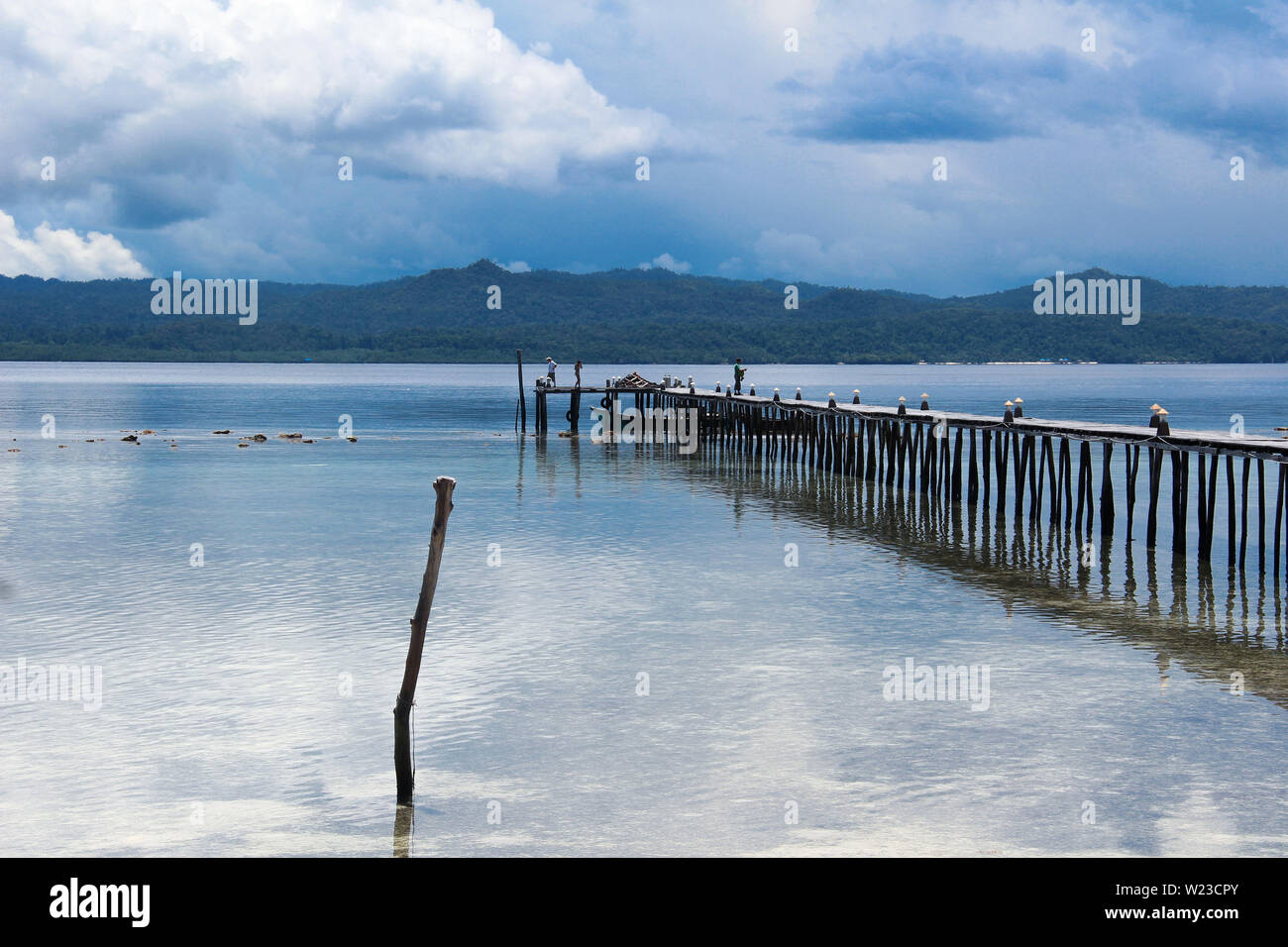 Traditional wooden jetty over calm water in the ocean near Kri Island ...