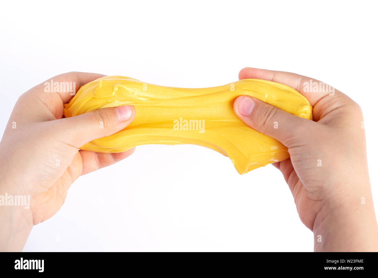 Children's hands stretch homemade goo and yellow slime. White ...
