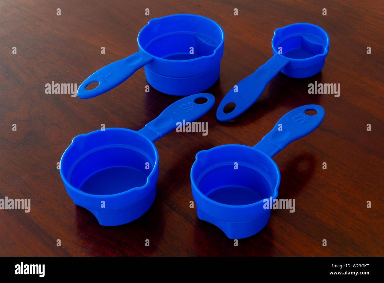 Four blue measuring spoons over a dark brown table Stock Photo - Alamy