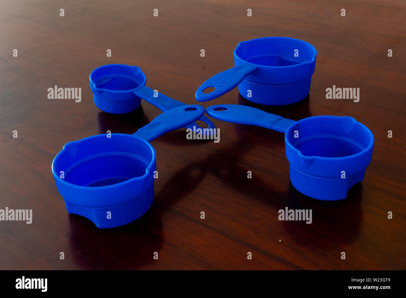 Four blue measuring spoons over a dark brown table Stock Photo - Alamy