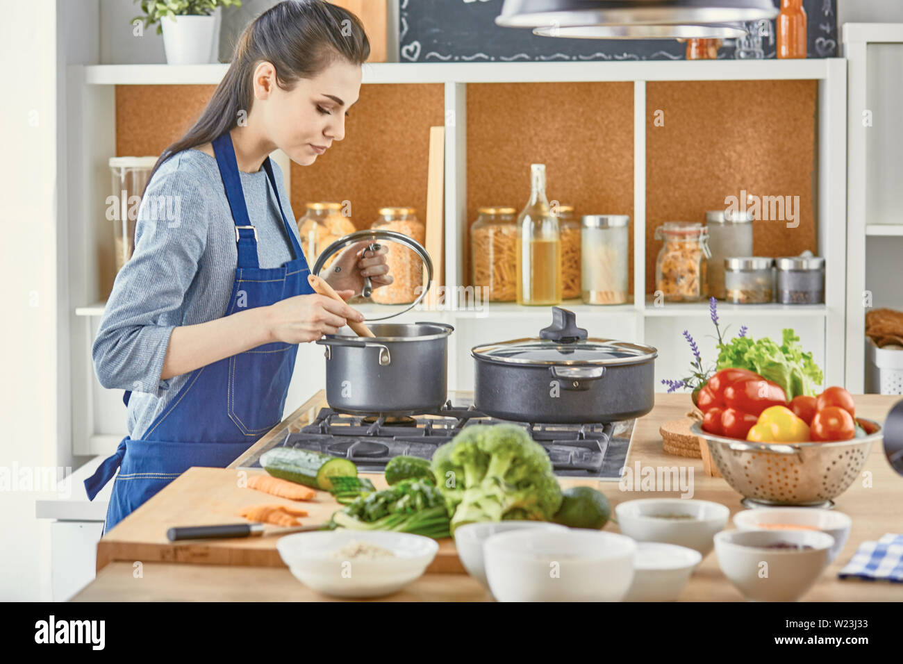 Beautiful girl is tasting food and smiling while cooking in kitchen at ...