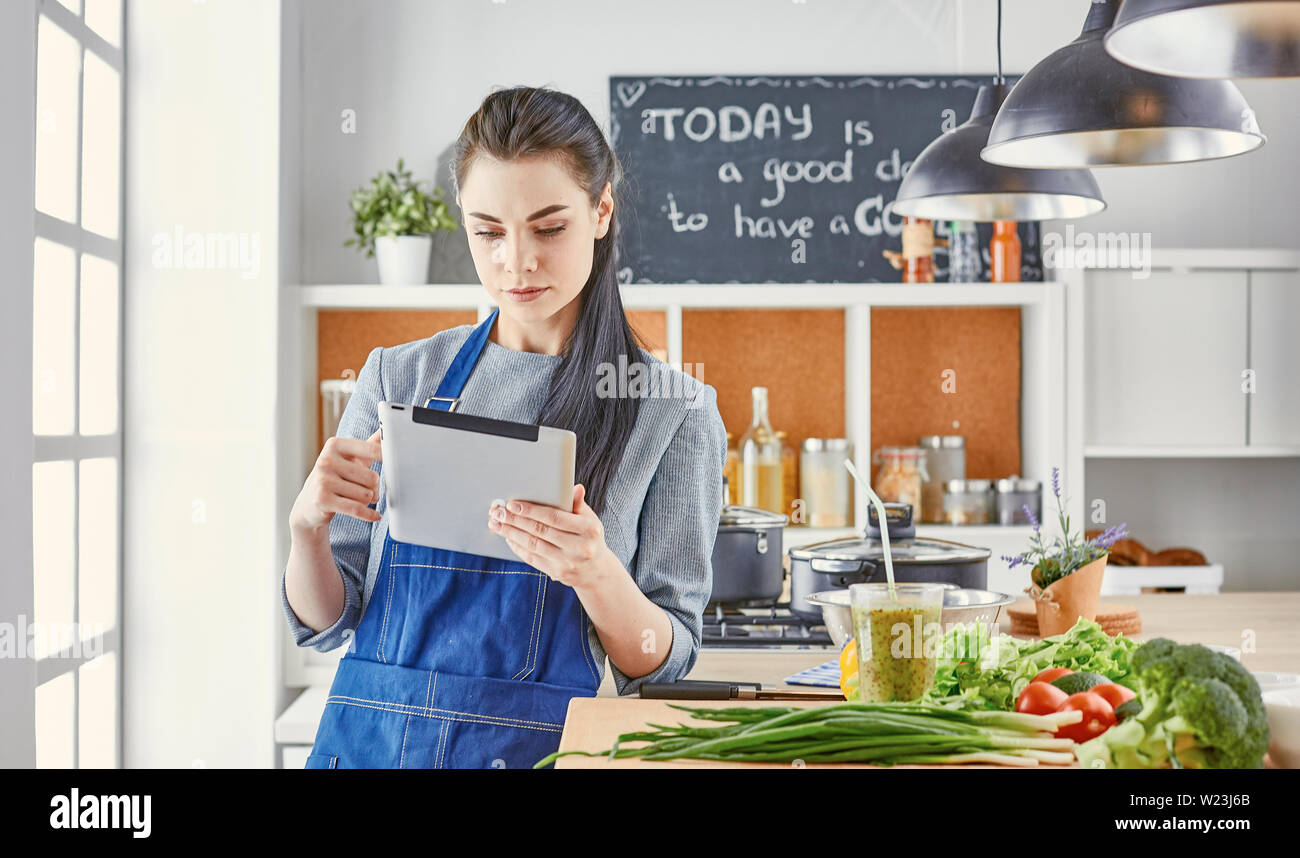 Happy woman looking recipe tablet kitchen reading cooking Stock Photo ...