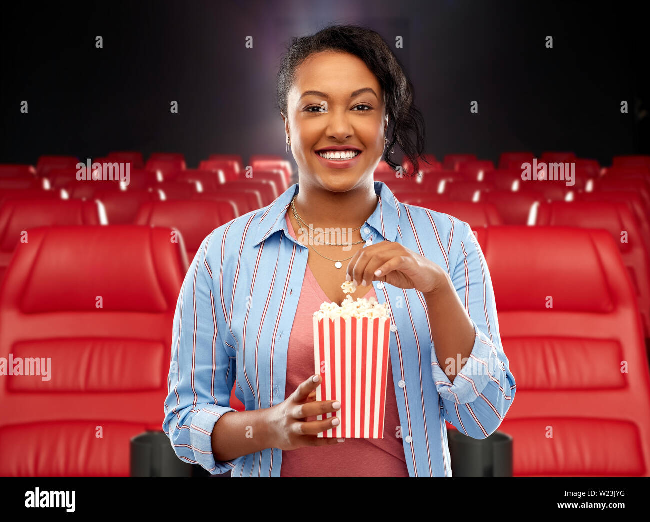 african woman eating popcorn at movie theater Stock Photo - Alamy