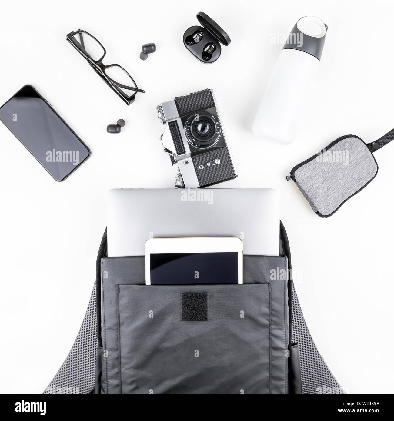 Creative top view flat lay of open backpack with laptop and tablet ...