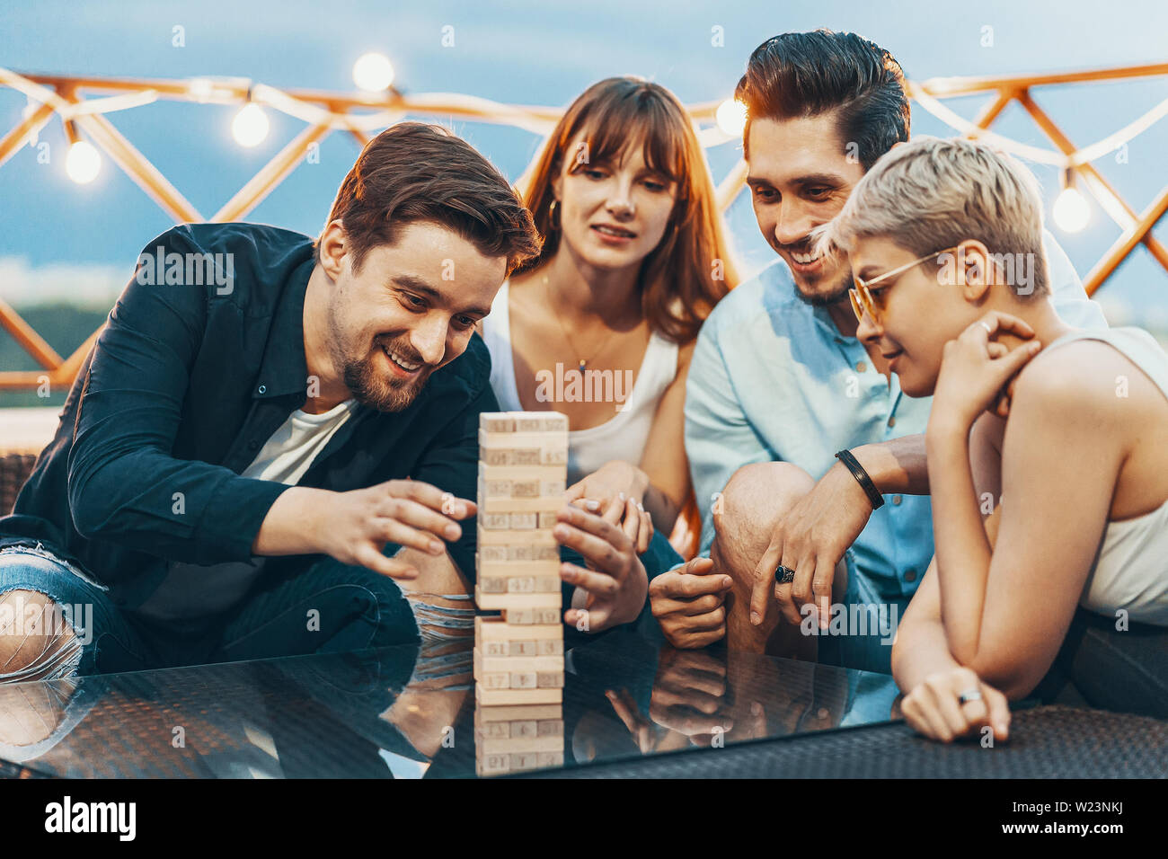 The company of young people playing jenga. Young friends at sunset on ...