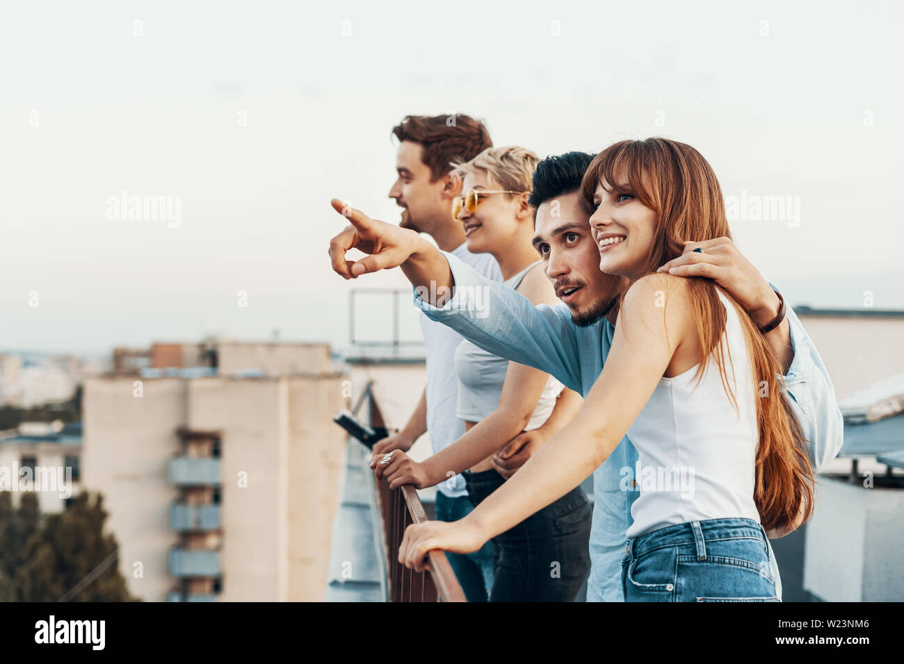 Group of friends enjoying outdoors at roof. Young friends at sunset on ...