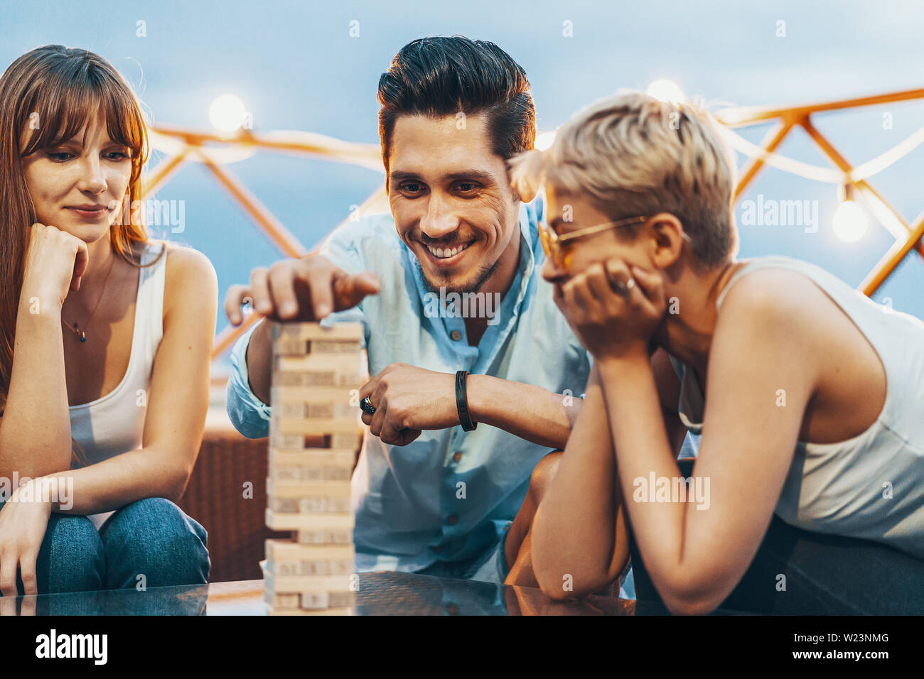 The company of young people playing jenga. Young friends at sunset on ...