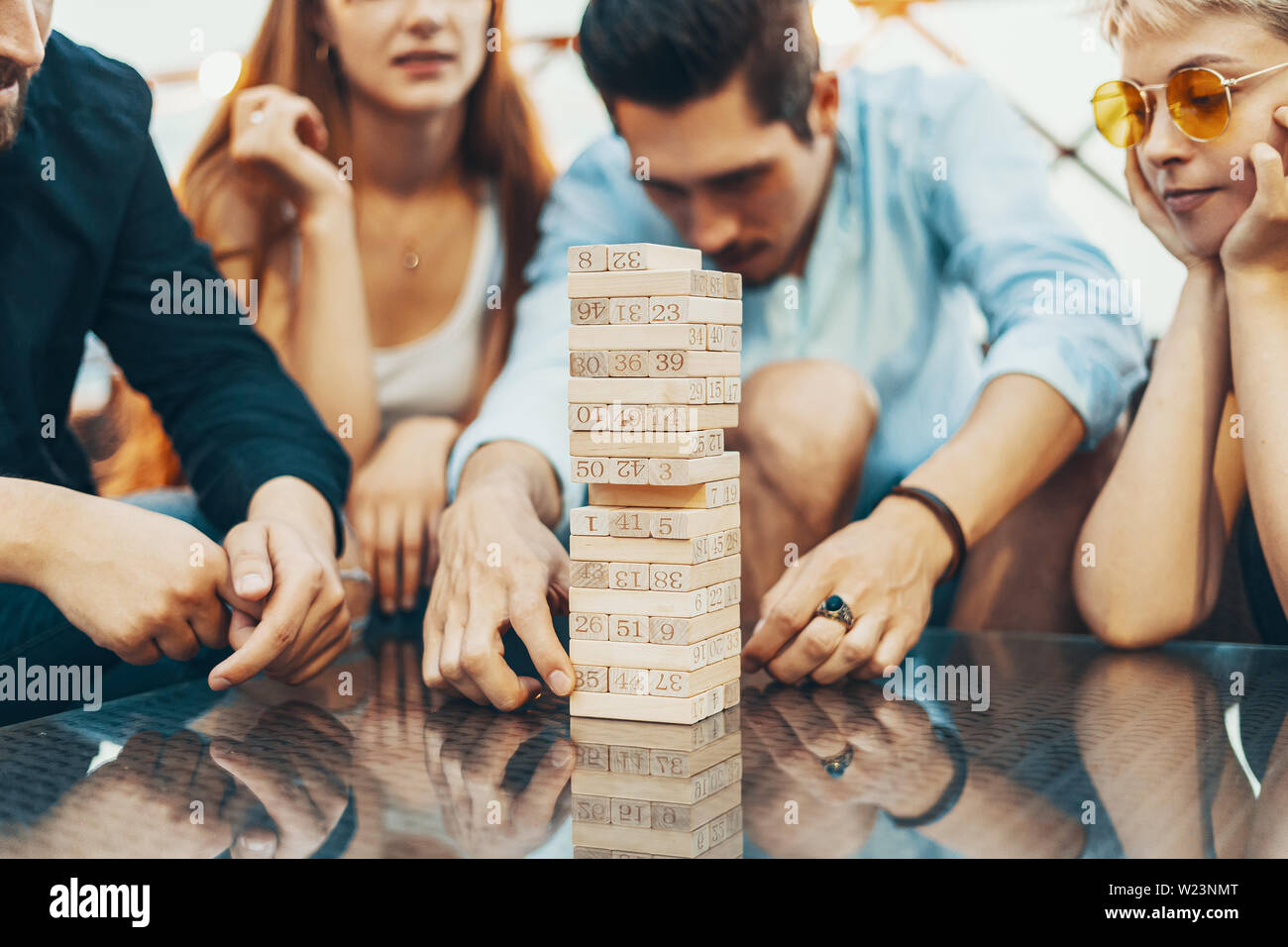 The company of young people playing jenga. Young friends at sunset on ...