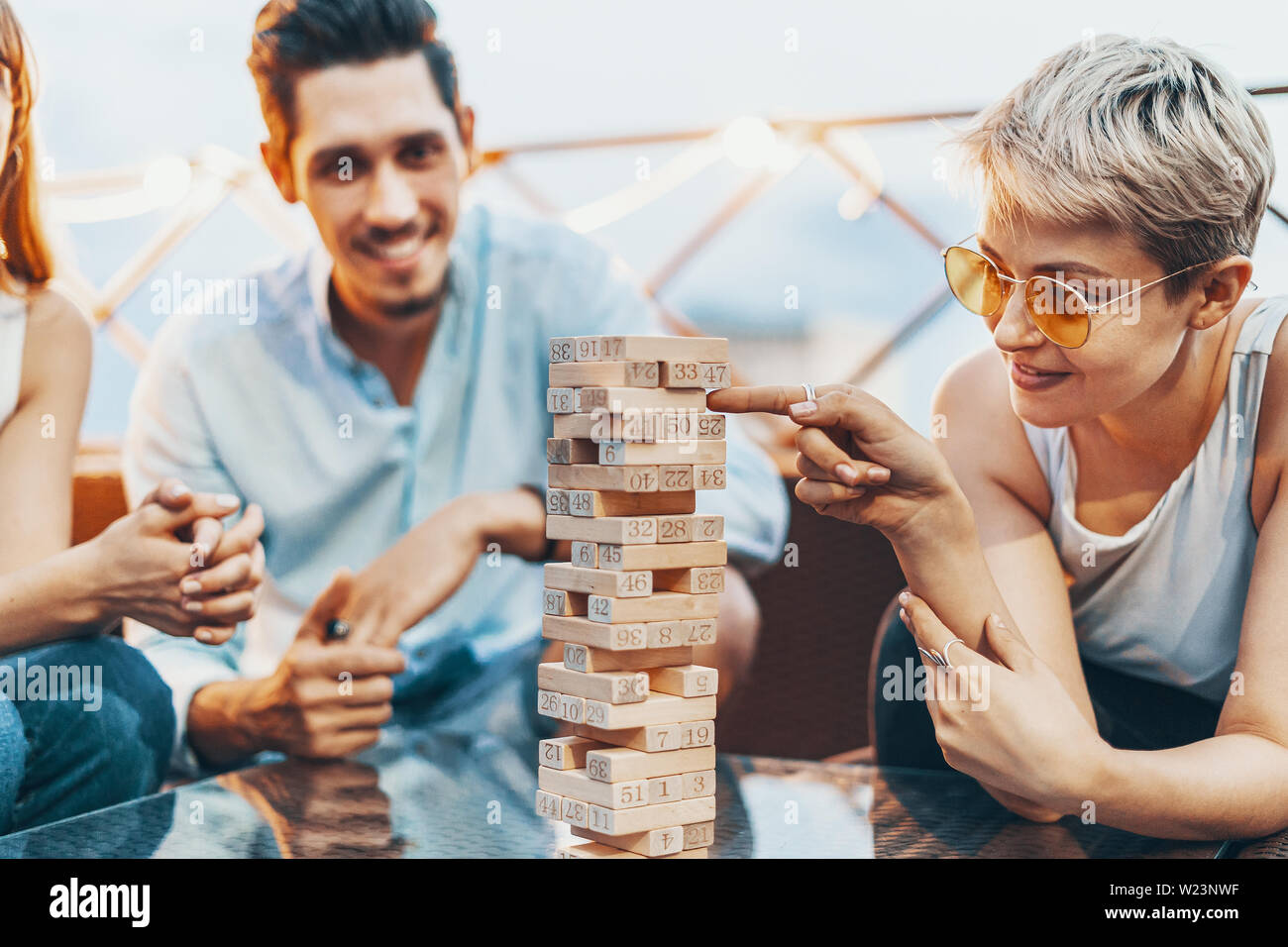 The company of young people playing jenga. Young friends at sunset on ...