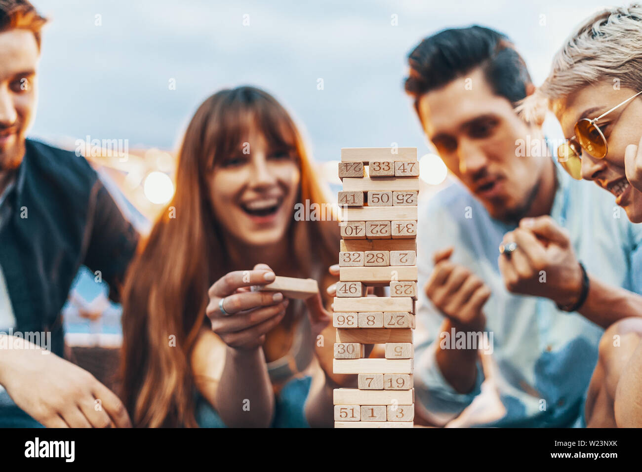 The company of young people playing jenga. Young friends at sunset on ...