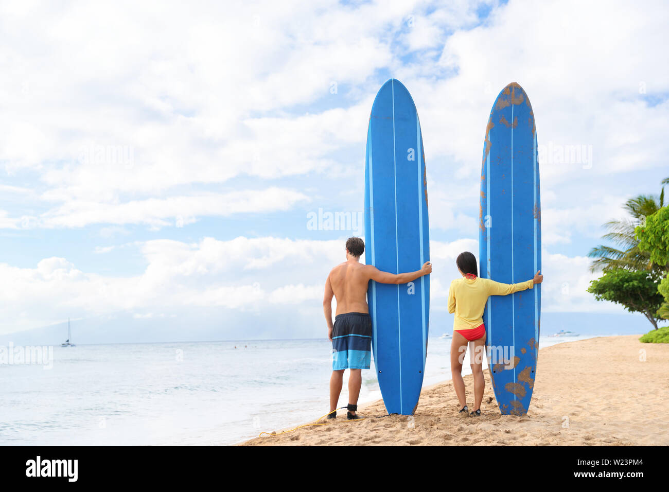 Two people young couple surfers standing with long blue surfboards on ...