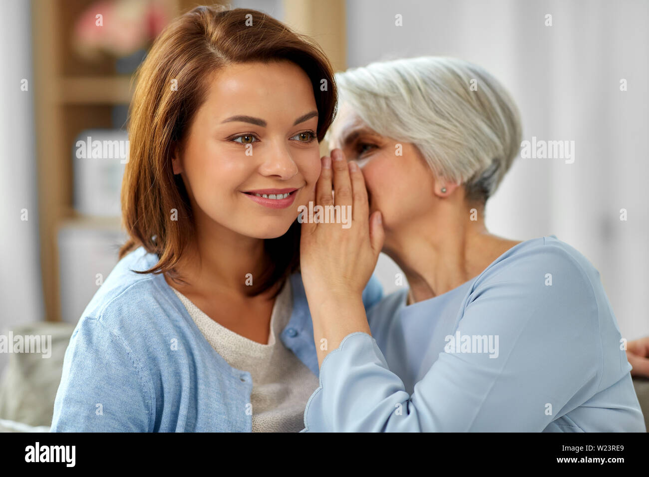 senior mother whispering to adult daughter at home Stock Photo - Alamy