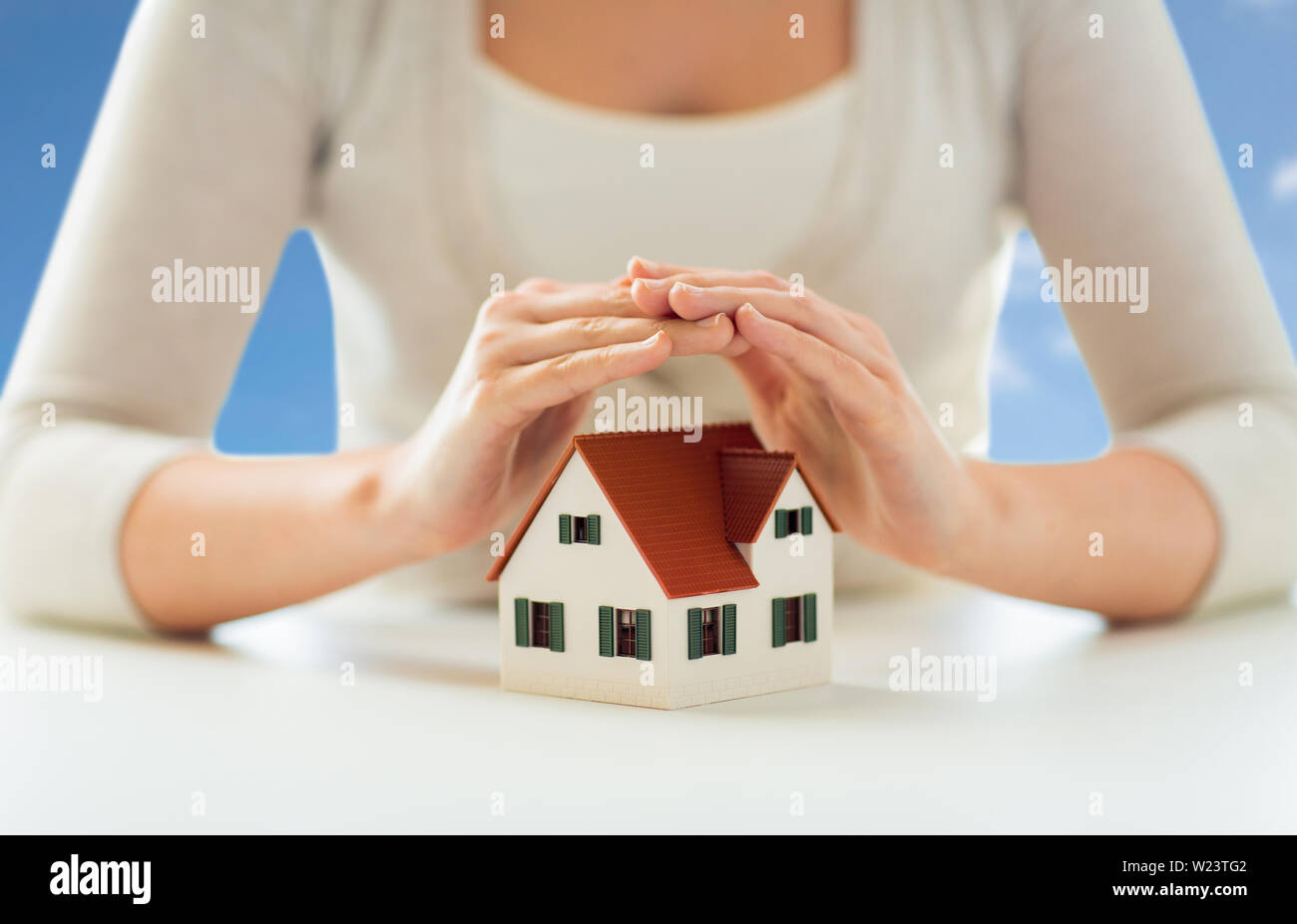 close up of woman protecting house model by hands Stock Photo - Alamy