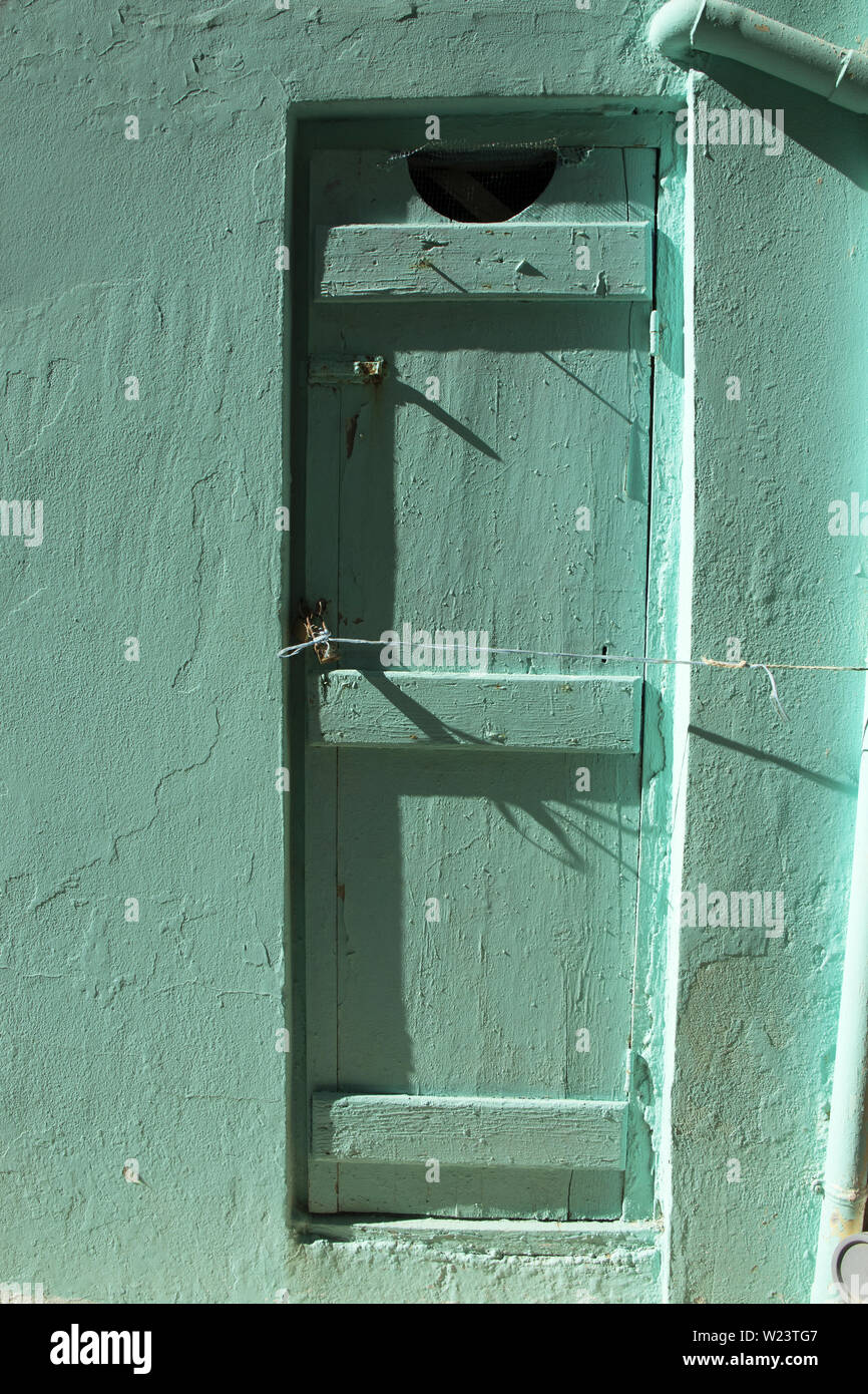 Green wall & narrow doorway painted all over in a narrow, sunlit street ...