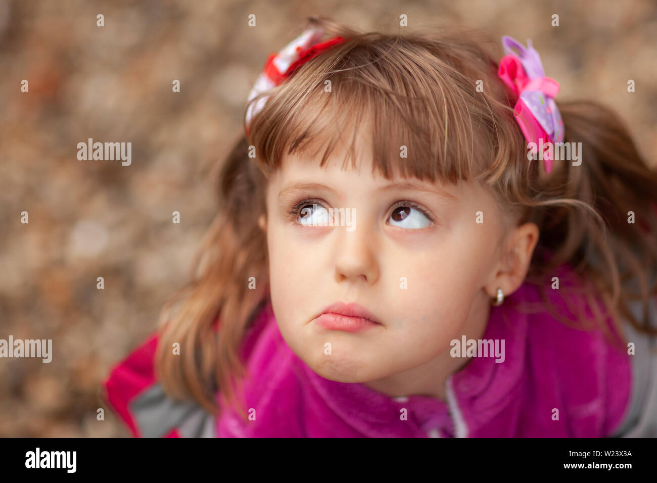Portrait of a cute Caucasian girl making grumpy face wearing pink ...