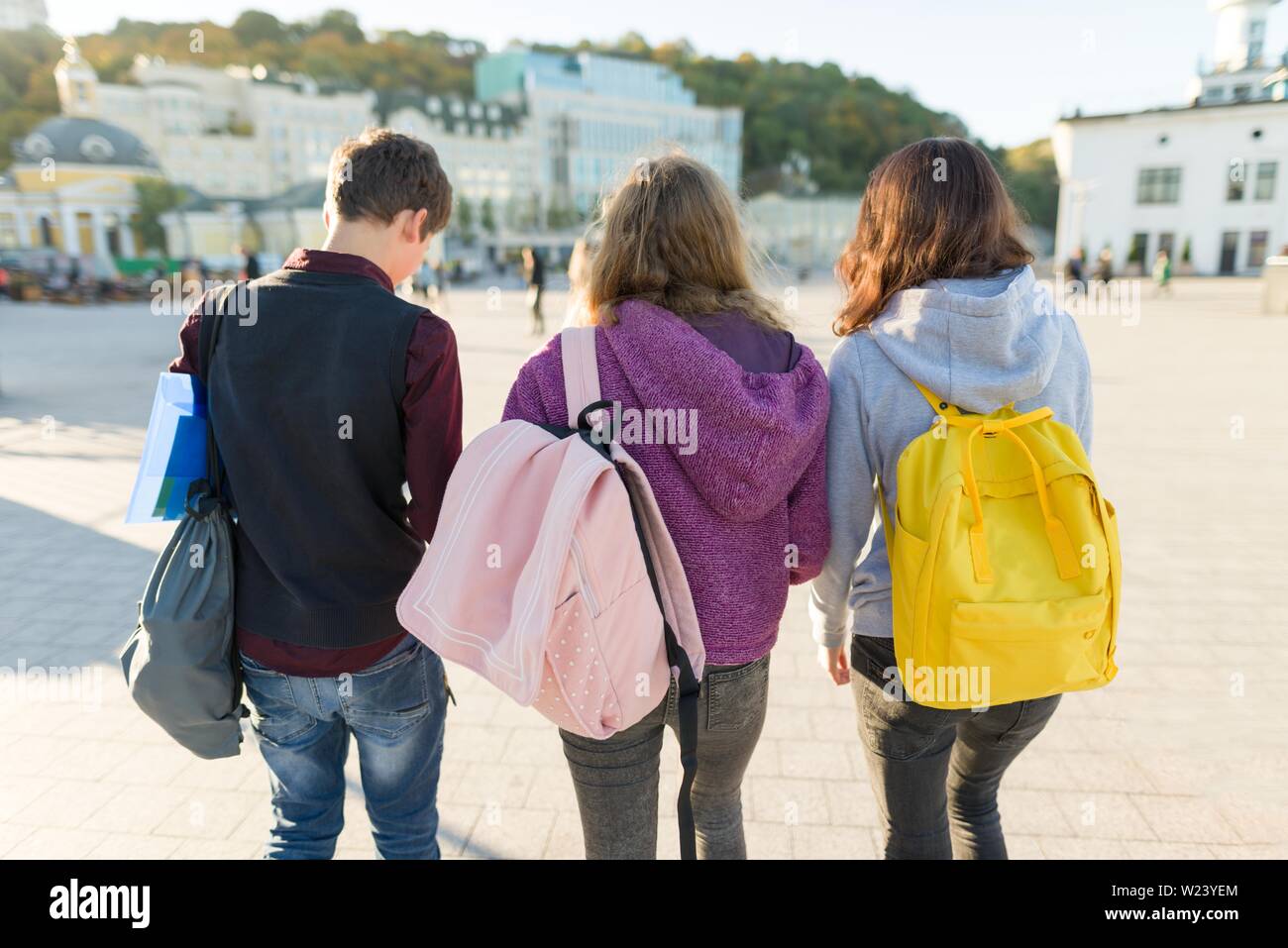 View from the back on three high school students with backpacks. City ...