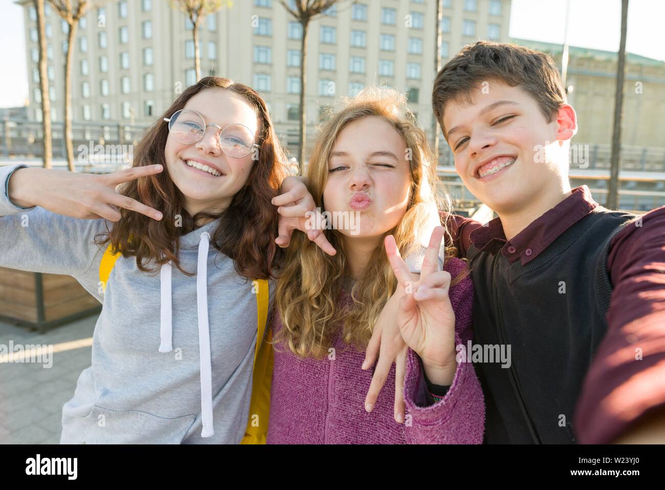 Portrait of friends teen boy and two girls smiling, making funny faces ...
