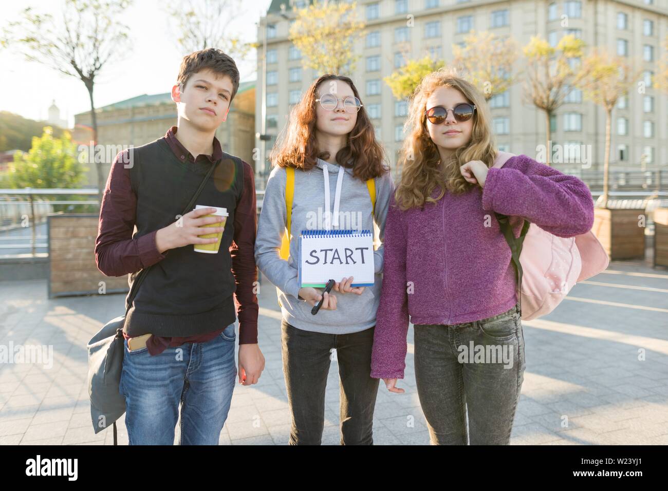 Group teenagers boy and two girls, with a notepad with handwritten word ...