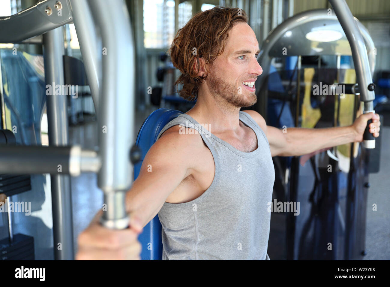 Man at fitness gym. Man doing workout on fitness machine at gym. Gym ...