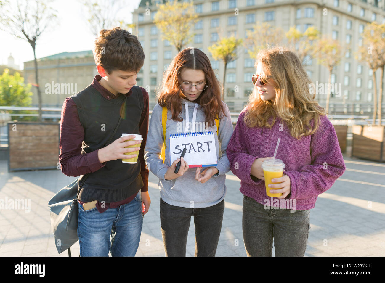 Group teenagers boy and two girls, with a notepad with handwritten word ...
