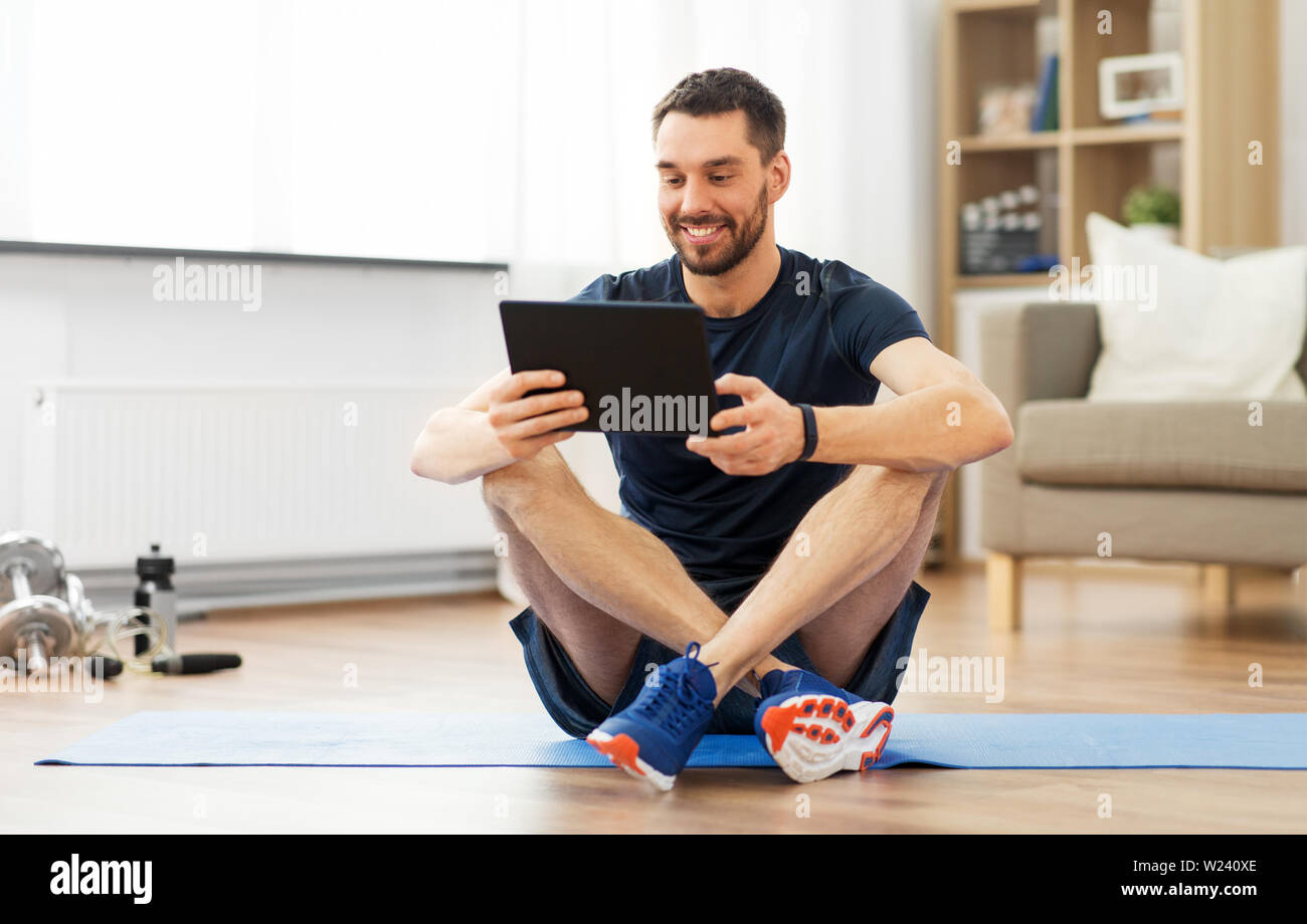 man with tablet computer on exercise mat at home Stock Photo - Alamy