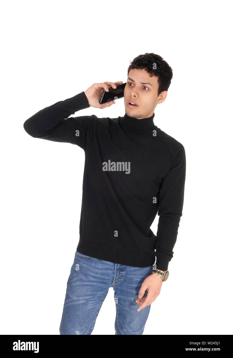 A young slim man in a black sweater and jeans standing, talking on the ...