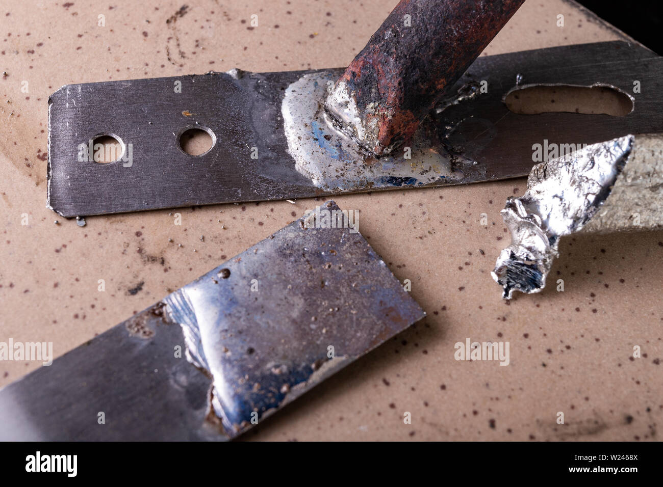 A large soldering iron and soldering accessories on a workshop table ...