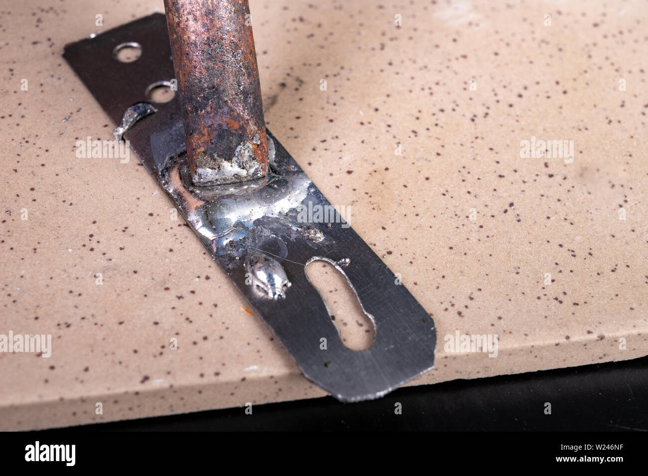 A large soldering iron and soldering accessories on a workshop table ...