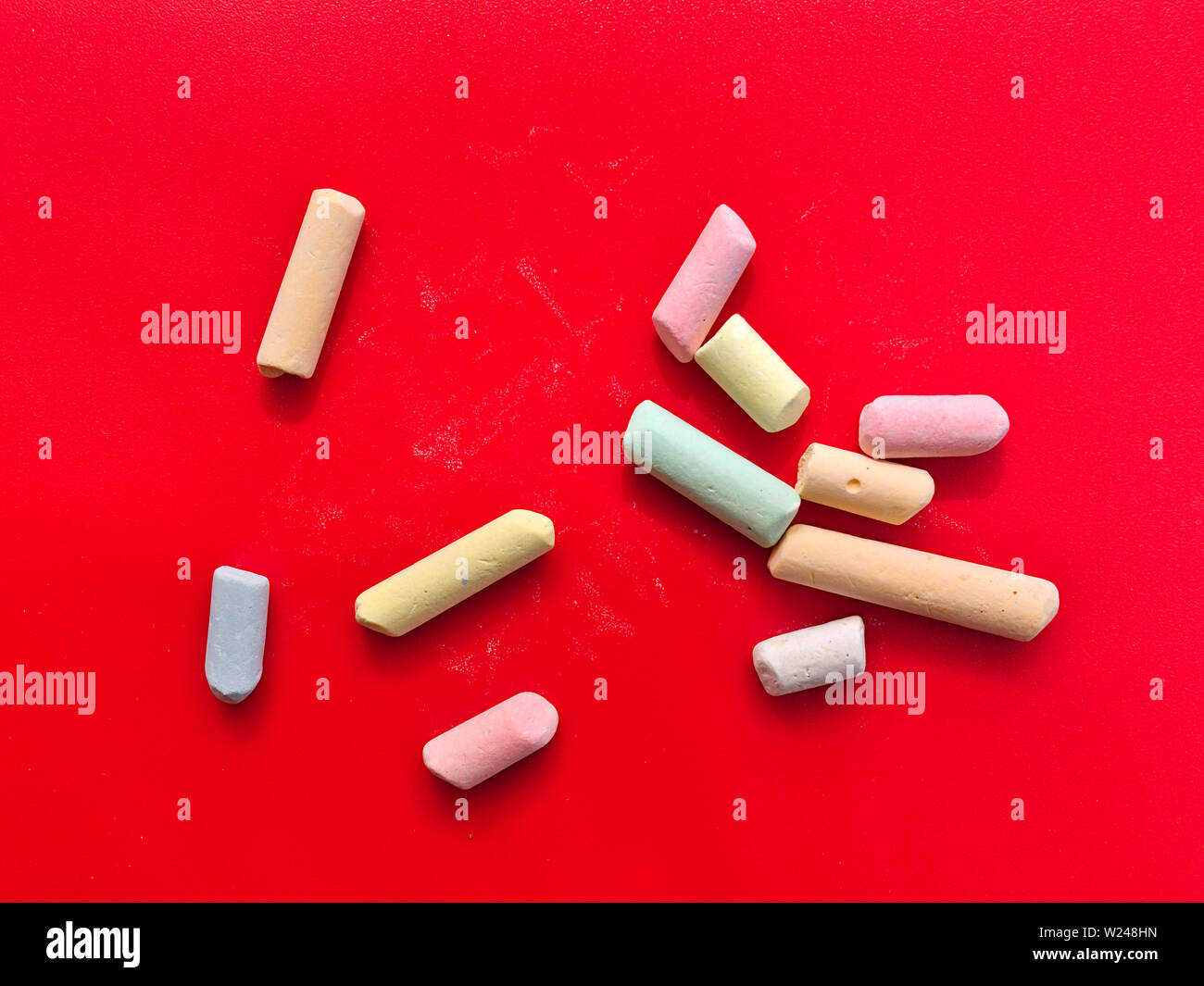 Broken multicolored chalk pieces isolated on red background Stock Photo ...