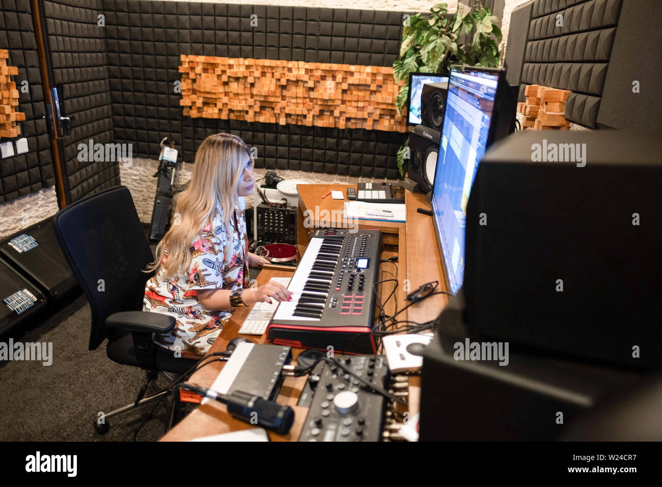female musician working in a modern music recording studio. playing on ...
