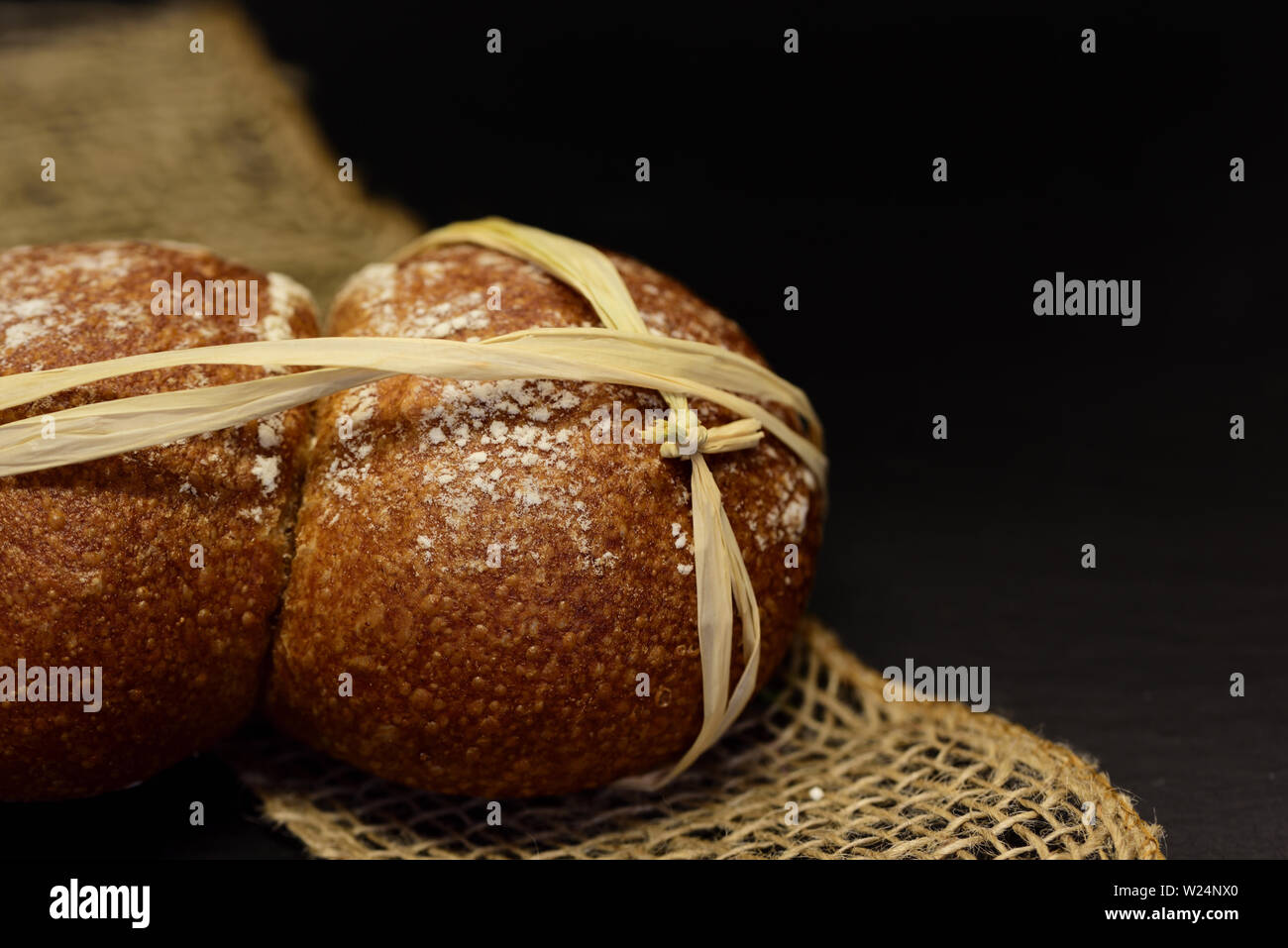 A bread in front of a dark background with a string wrapped around to ...