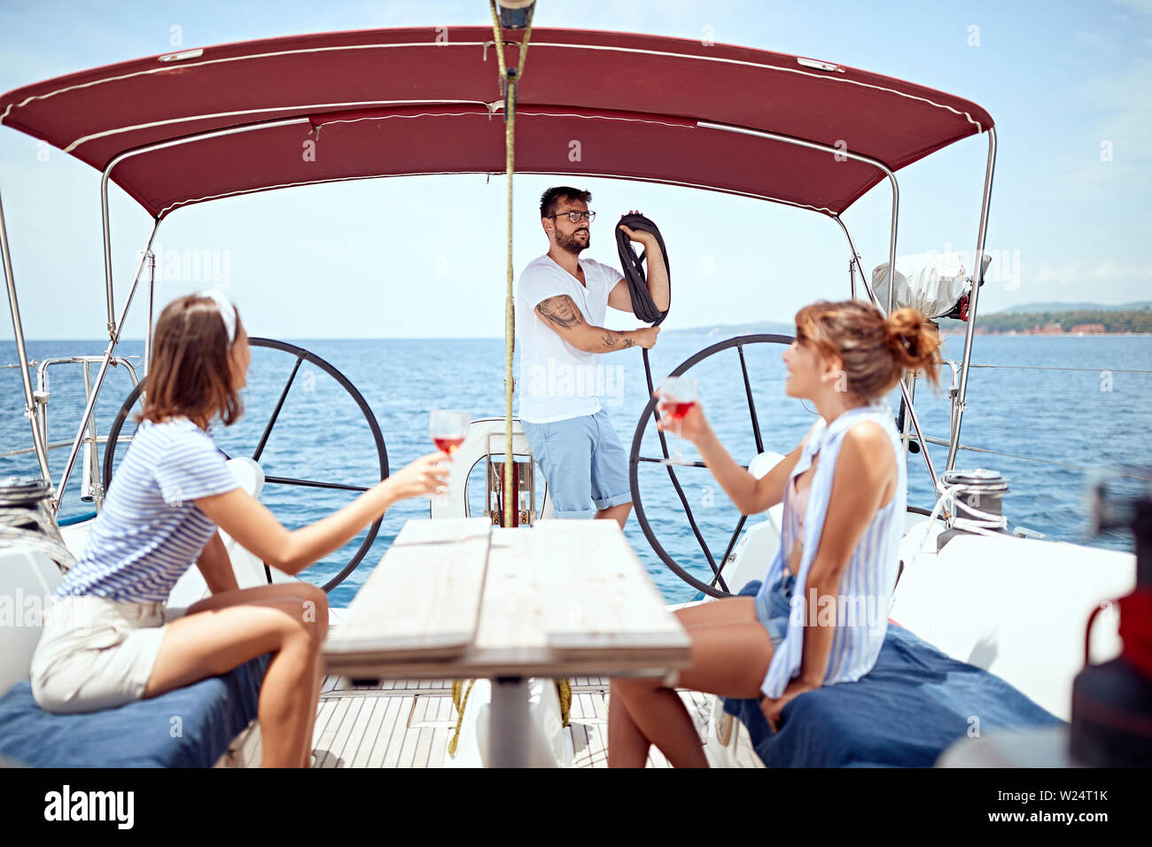 young friends sailing in a sea on the yacht and enjoying on summer day ...