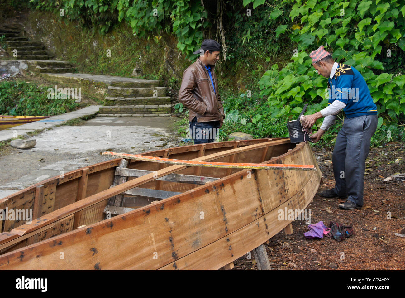 Craftsman applying pitch (sealant) to unfinished boat at Begnas Tal ...