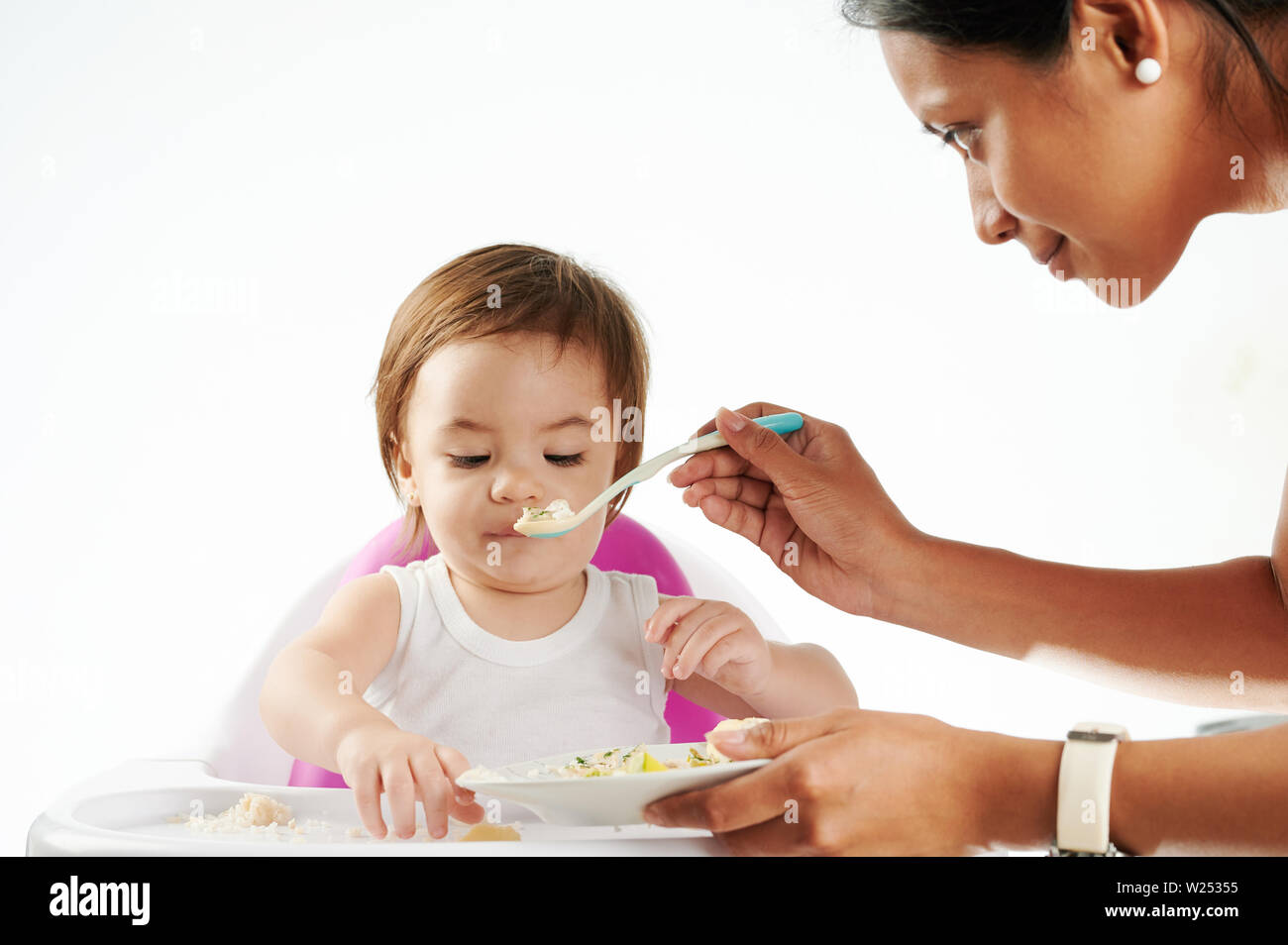 Baby sitter feed small baby isolated in studio background Stock Photo ...