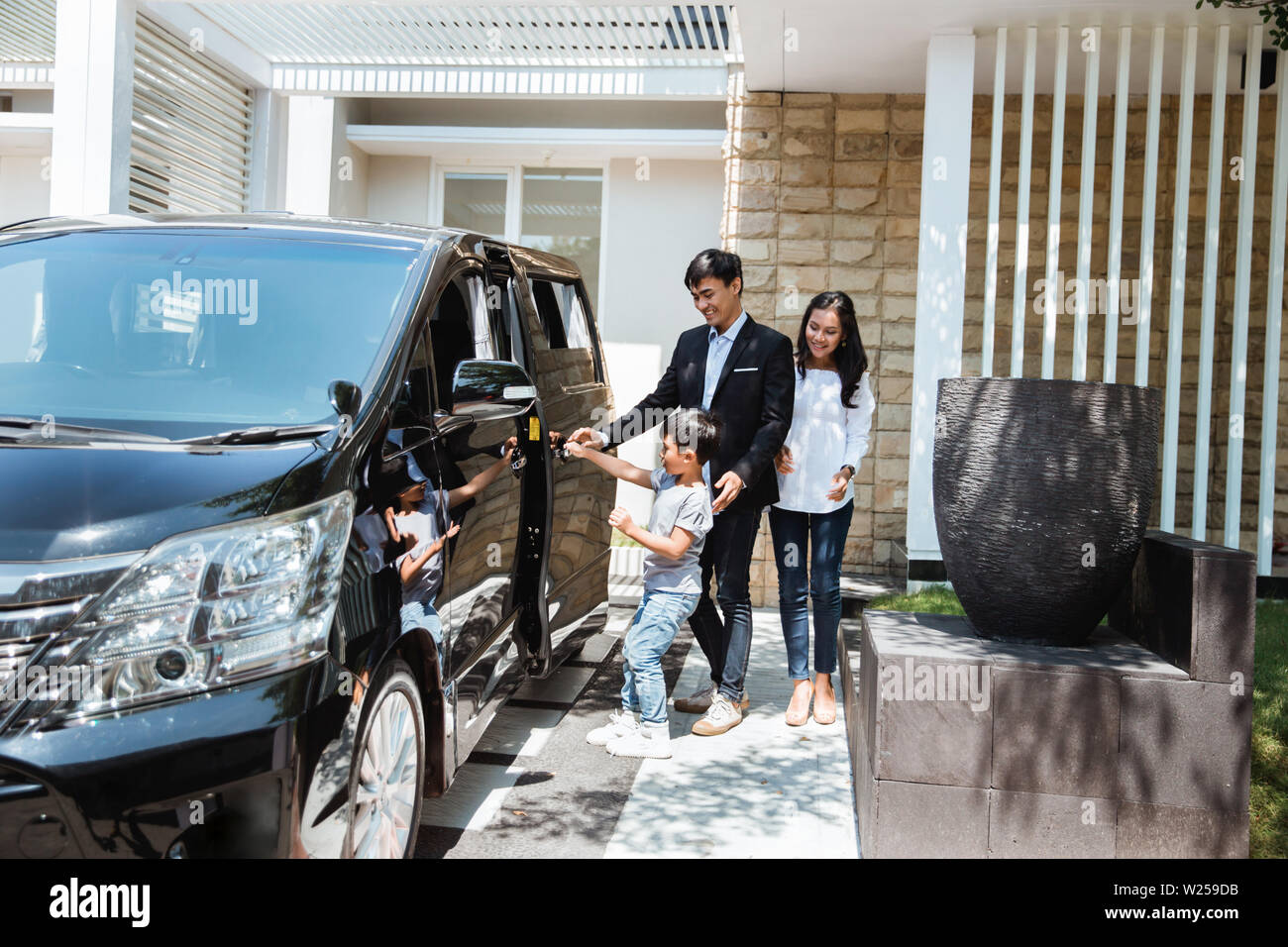 parent with kid in front of their car smiling to camera Stock Photo - Alamy