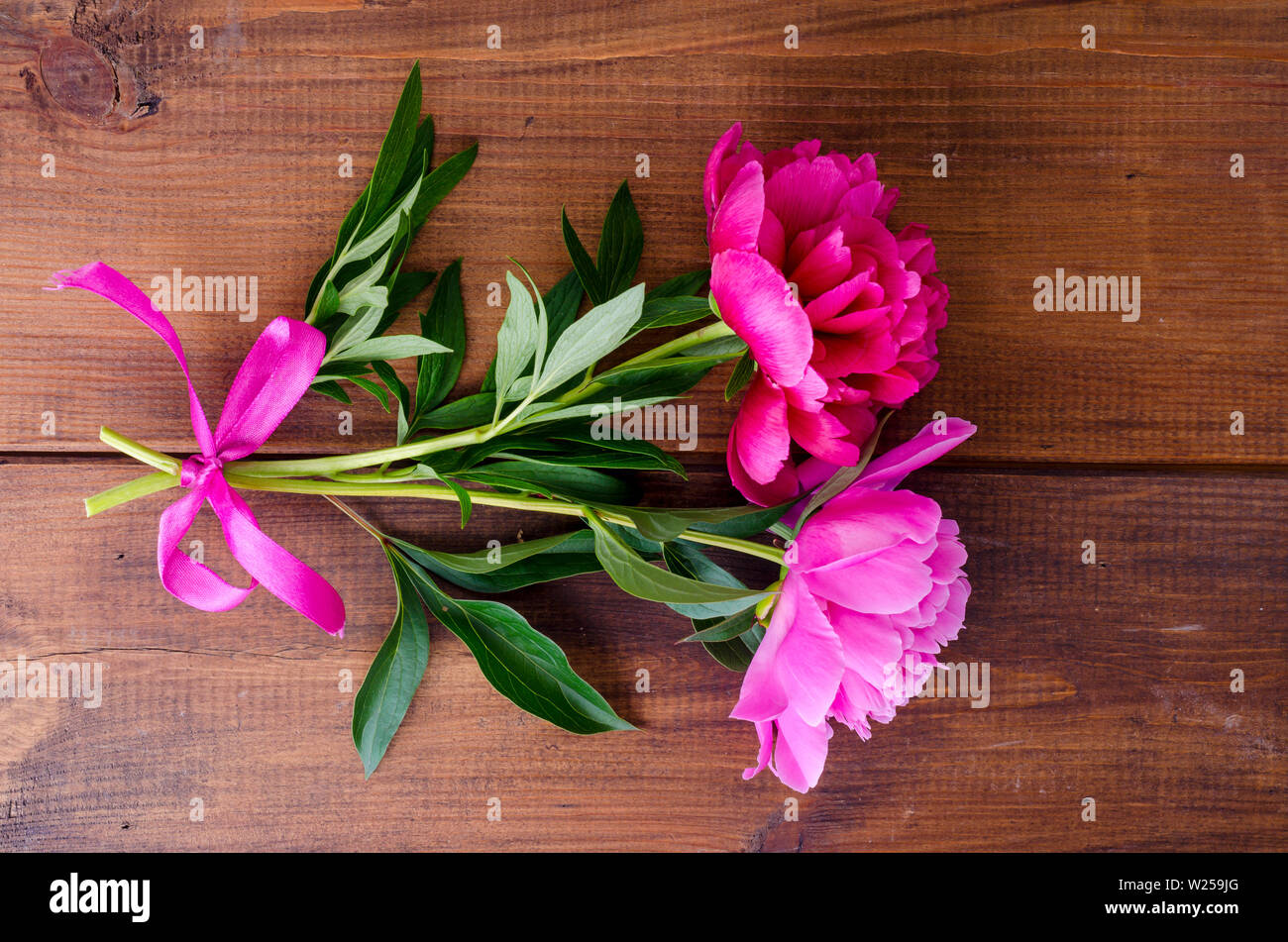 Two beautiful peonies with ribbon on wooden table Stock Photo - Alamy