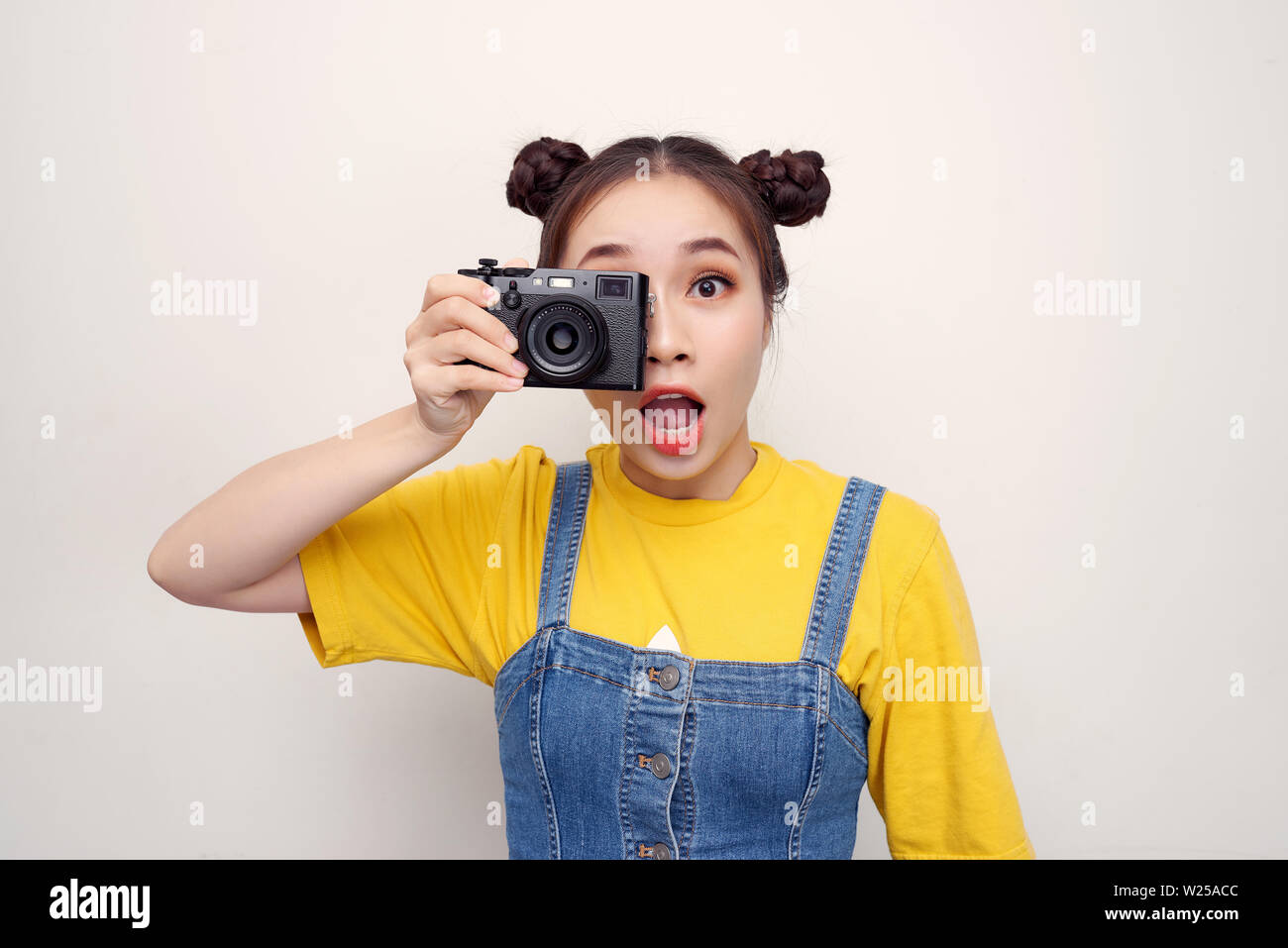 Image of excited paparazzi girl holding retro camera at face and ...