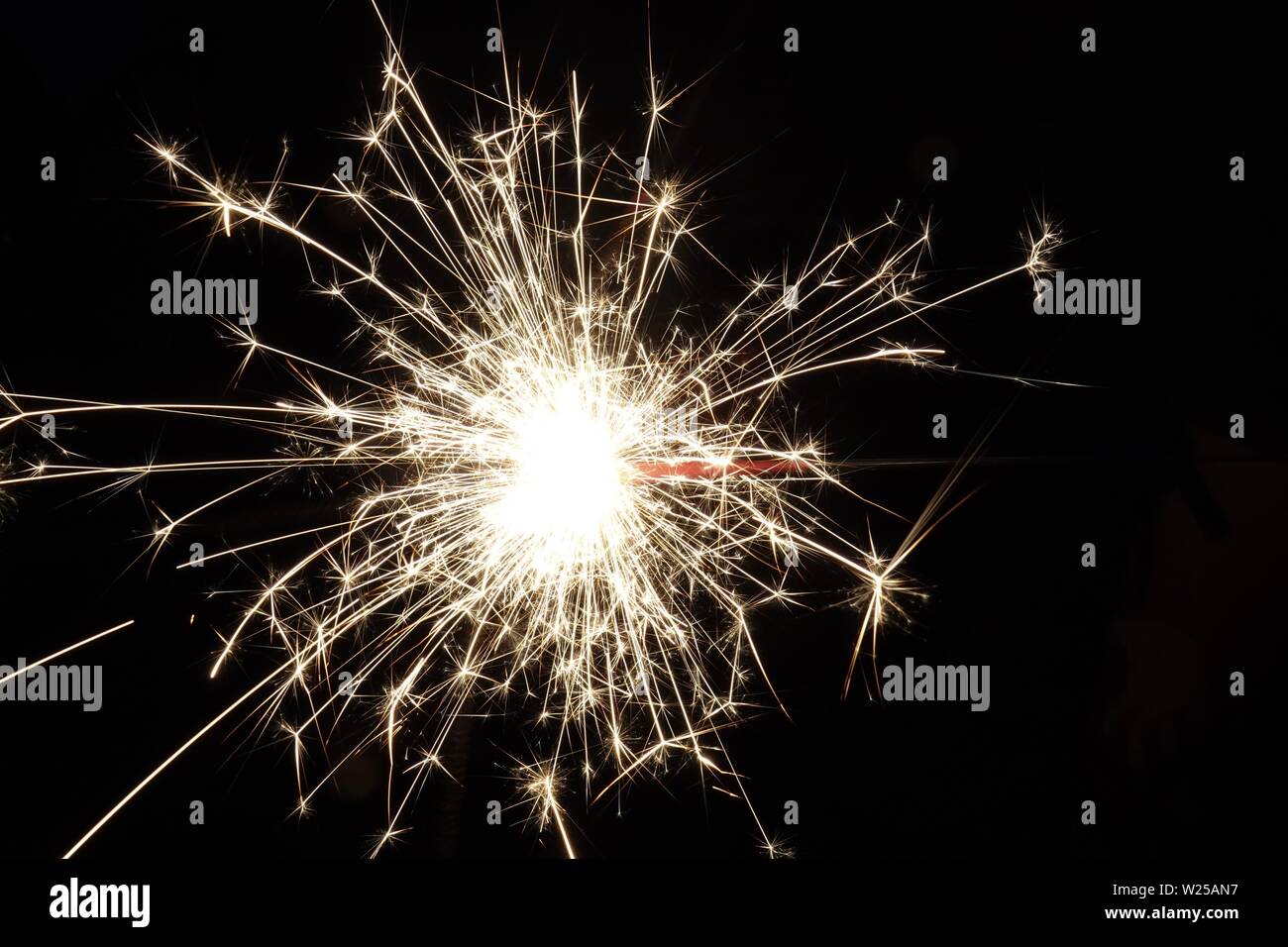 A sparkler is lit and emits colorful flames and sparks Stock Photo - Alamy