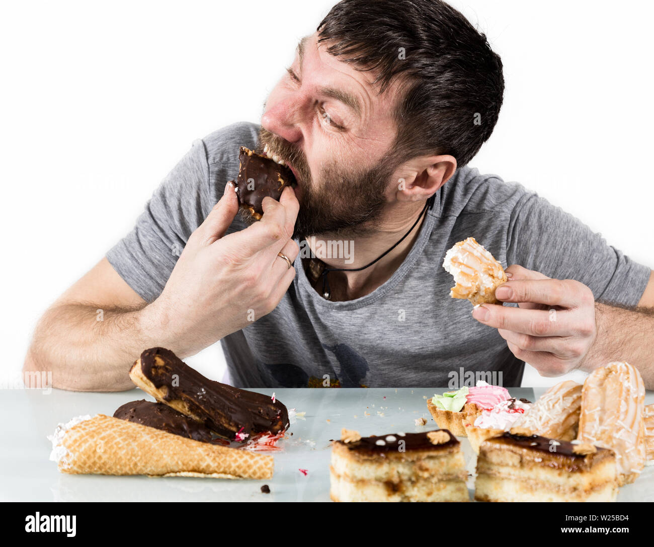 glutton bearded man eating cupcakes with frenzy after long diet ...