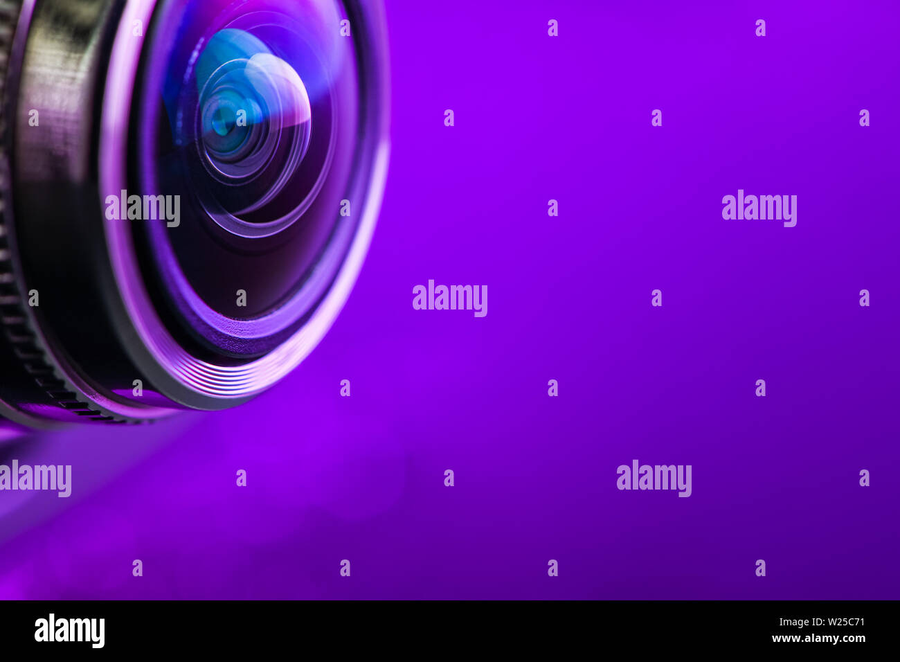 Camera lens and dark purple backlight. Side view of the lens of camera ...