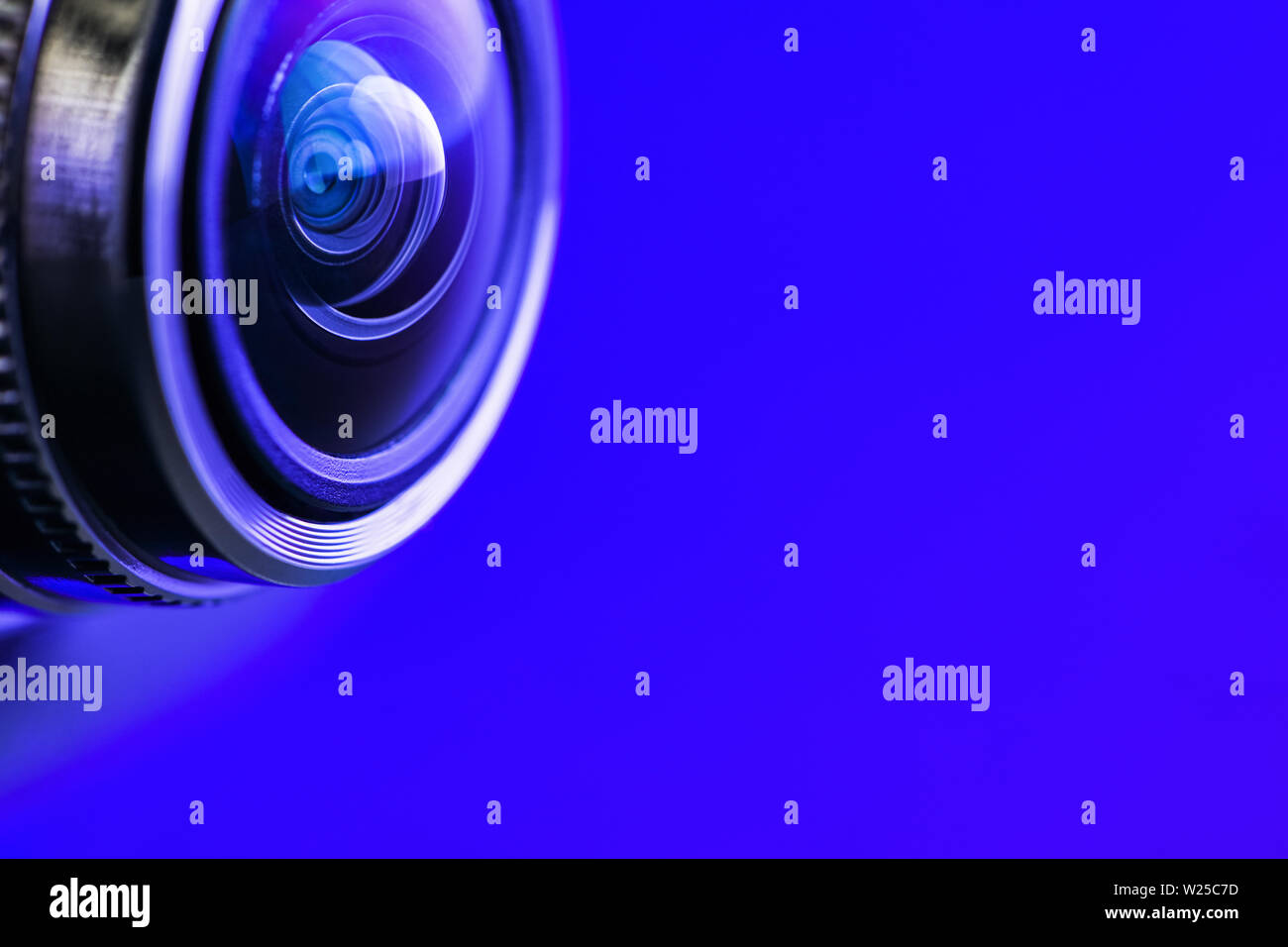 Camera lens and dark blue backlight. Side view of the lens of camera on ...